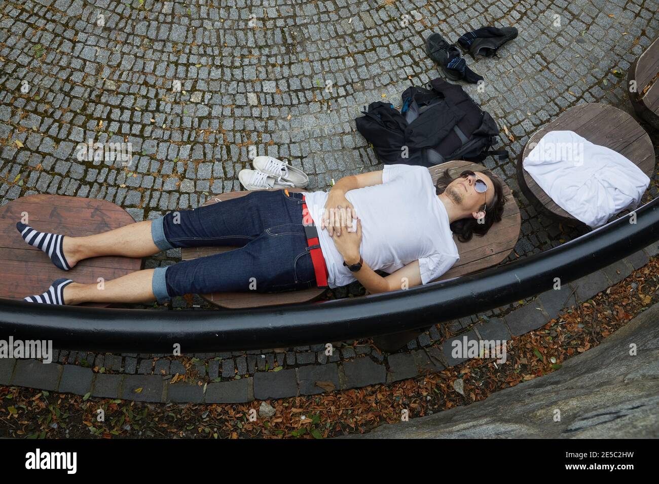 Man lying on a park bench in summer Stock Photo - Alamy