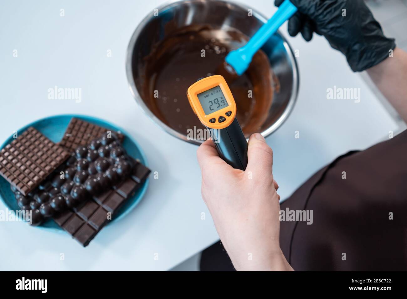 closeup of female measuring temperature of melted chocolate with ...