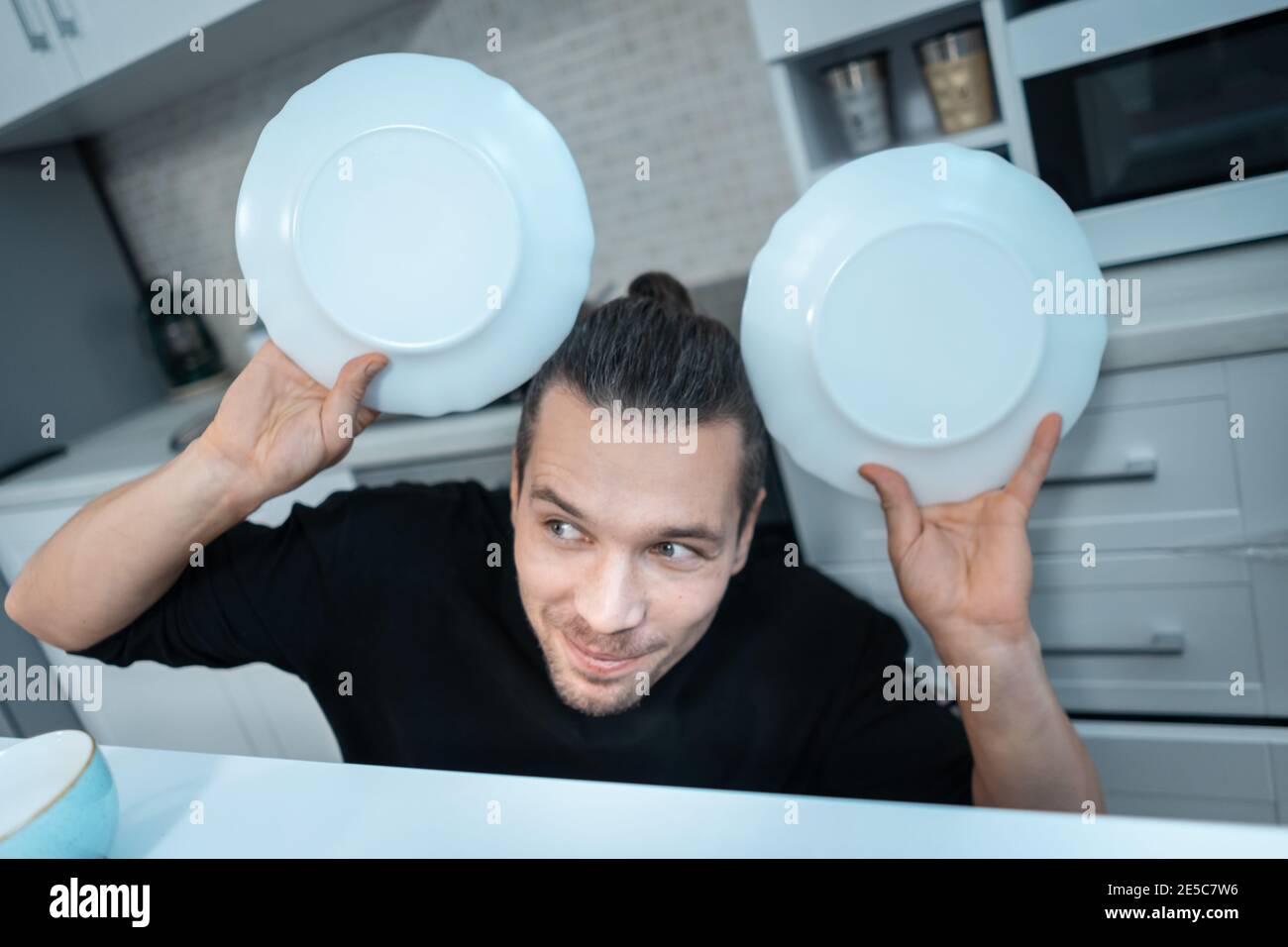attractive hungry young man on modern kitchen with empty plate, fork ...