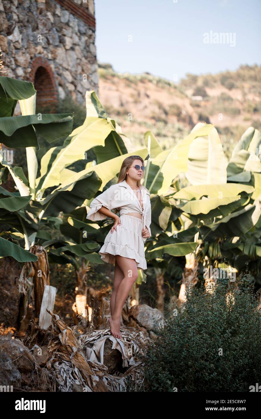 Exotic tropical woman near green leaves of banana bush. Tropical island ...