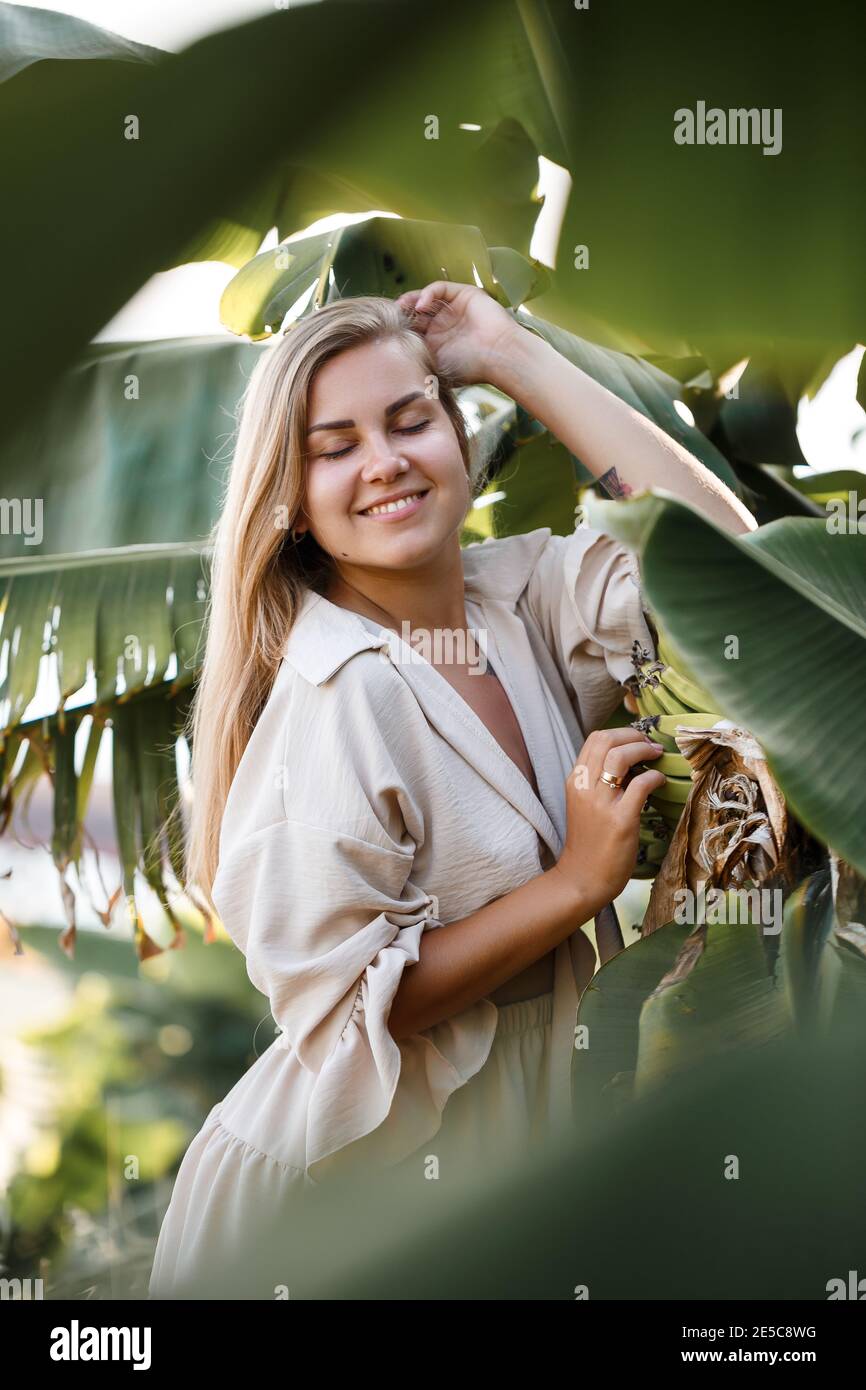 Exotic tropical woman near green leaves of banana bush. Tropical island ...