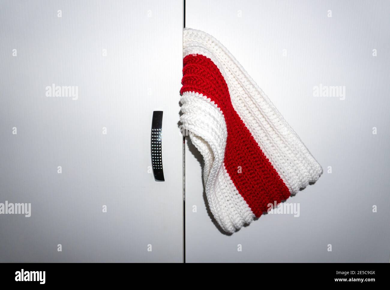 Knitted scarf white red white hanging from cabinet doors Stock Photo ...