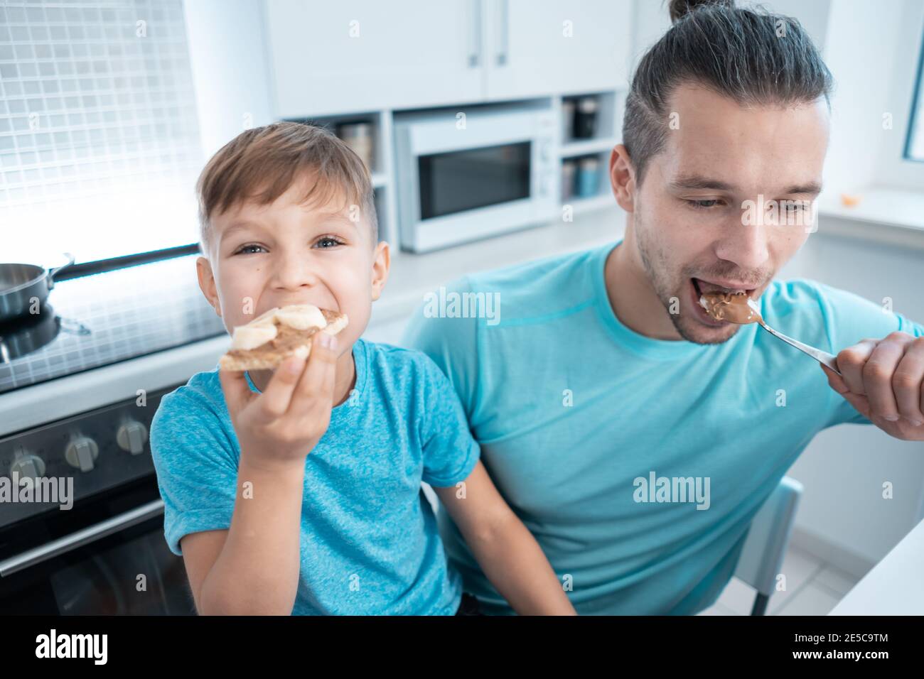 happy kid boy and father eating healthy peanut butter toast at home ...