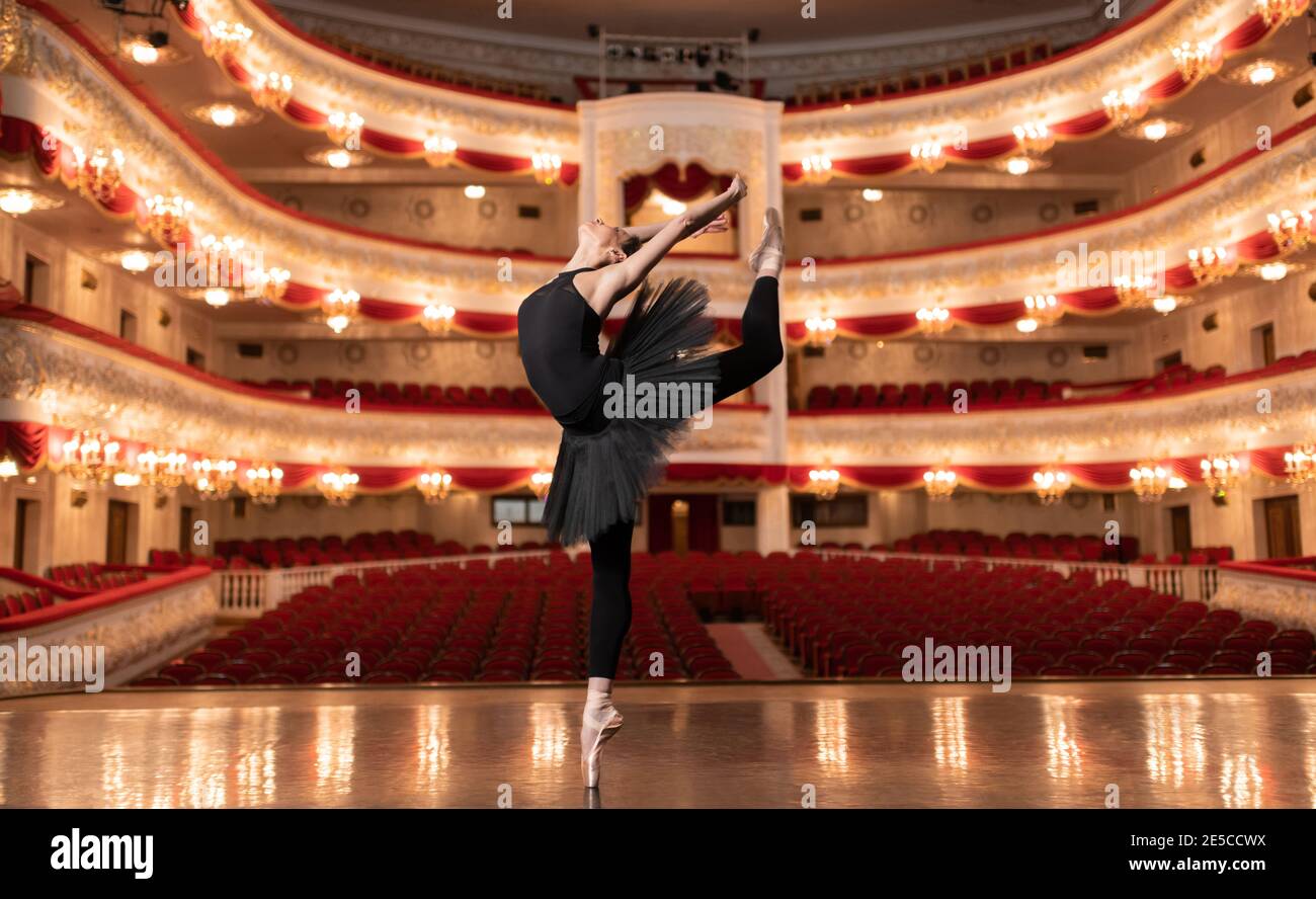 Slim adult woman raising arms and leg while dancing ballet in empty ...