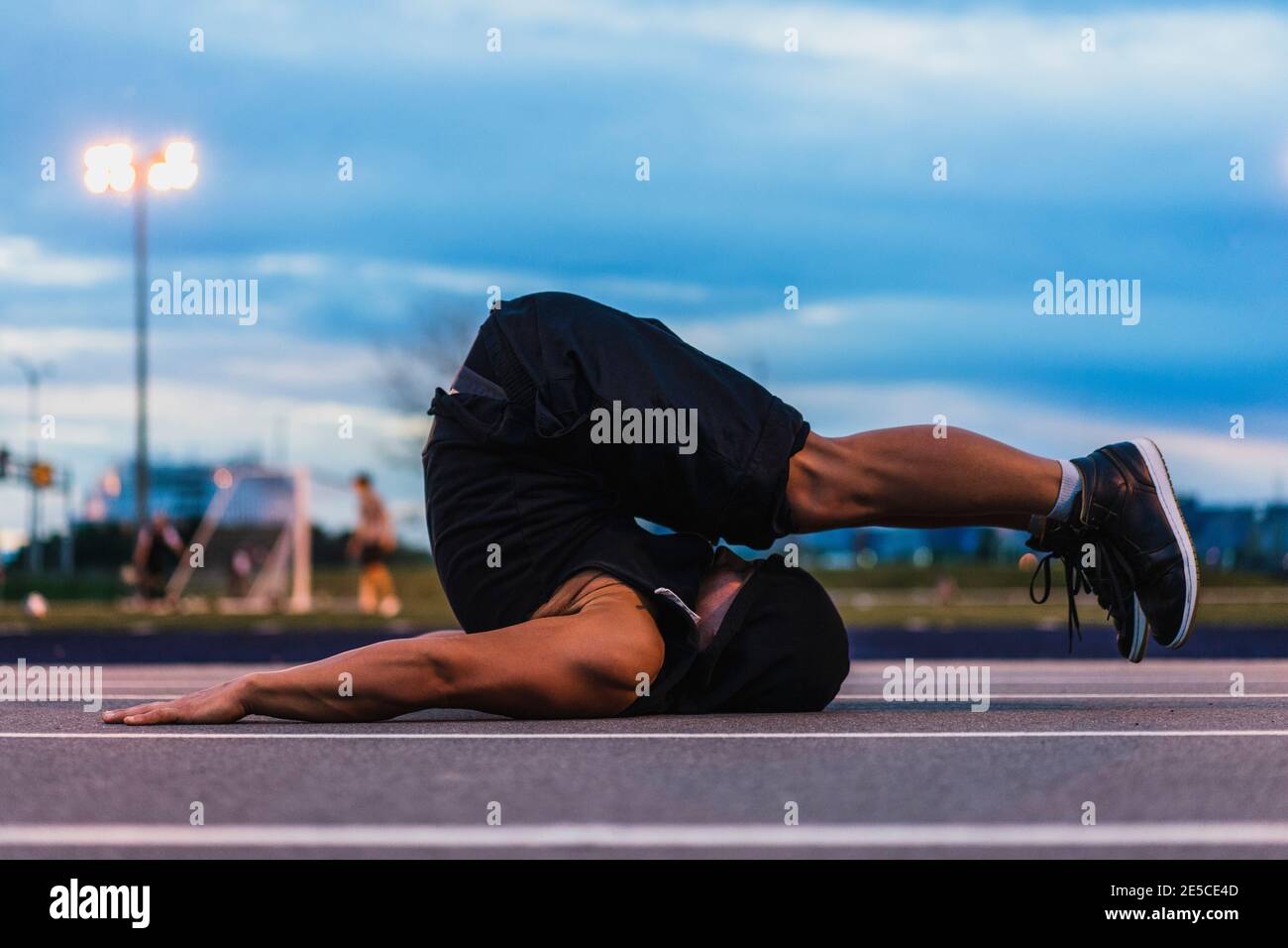 Athletic man stretching back while working out on track at night ...
