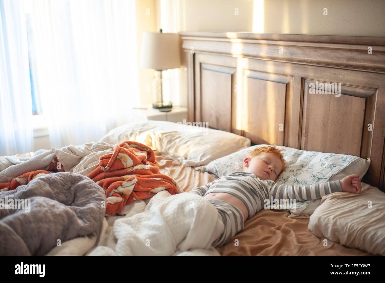 Toddler boy 3-4 years old asleep in messy parents bed in pretty light ...