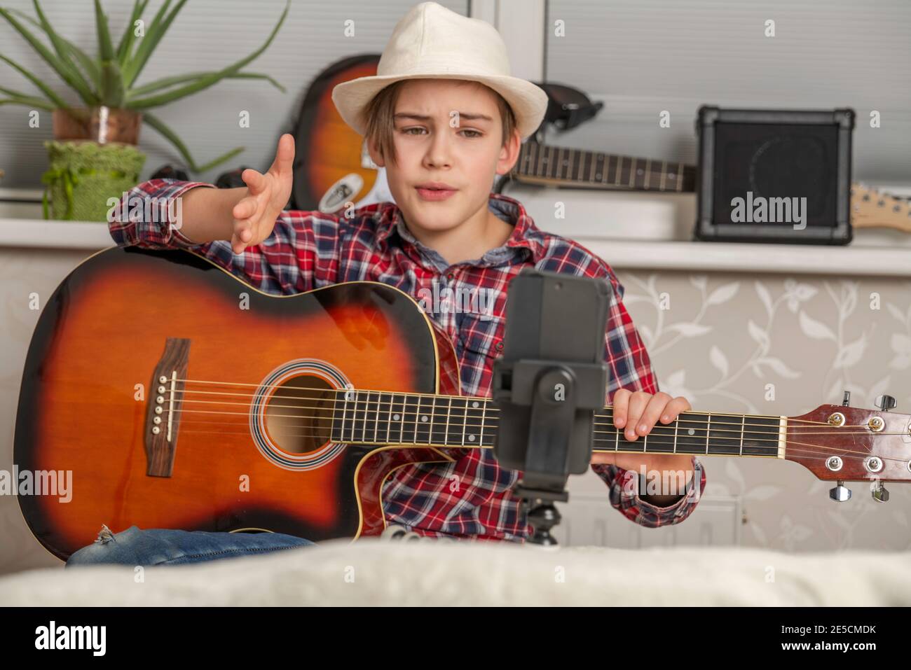 Boy learning or takes off the vlog to play guitar through a video call ...