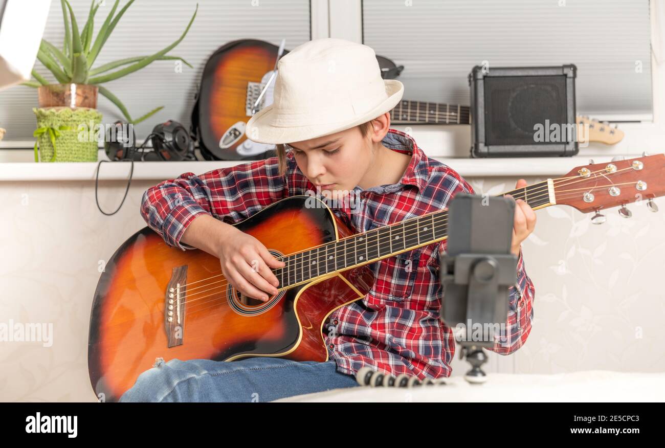 Boy learning or takes off the vlog to play guitar through a video call ...