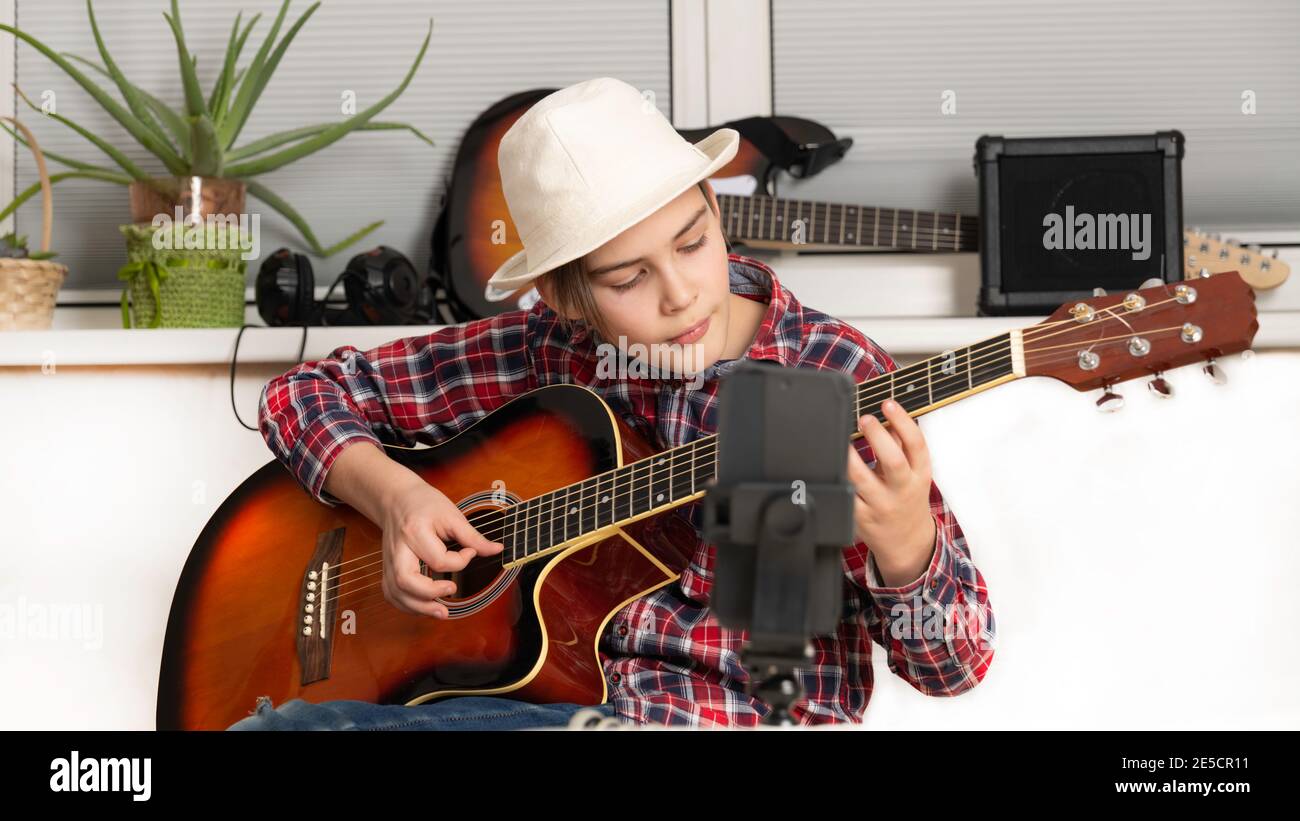 Boy learning or takes off the vlog to play guitar through a video call ...