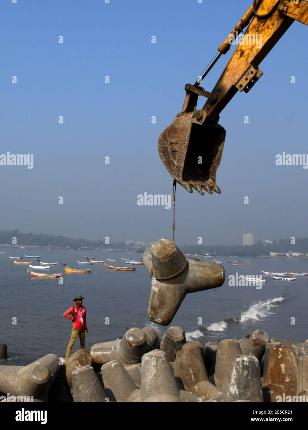 A construction equipment carries a tetrapod rock during the arrangement ...