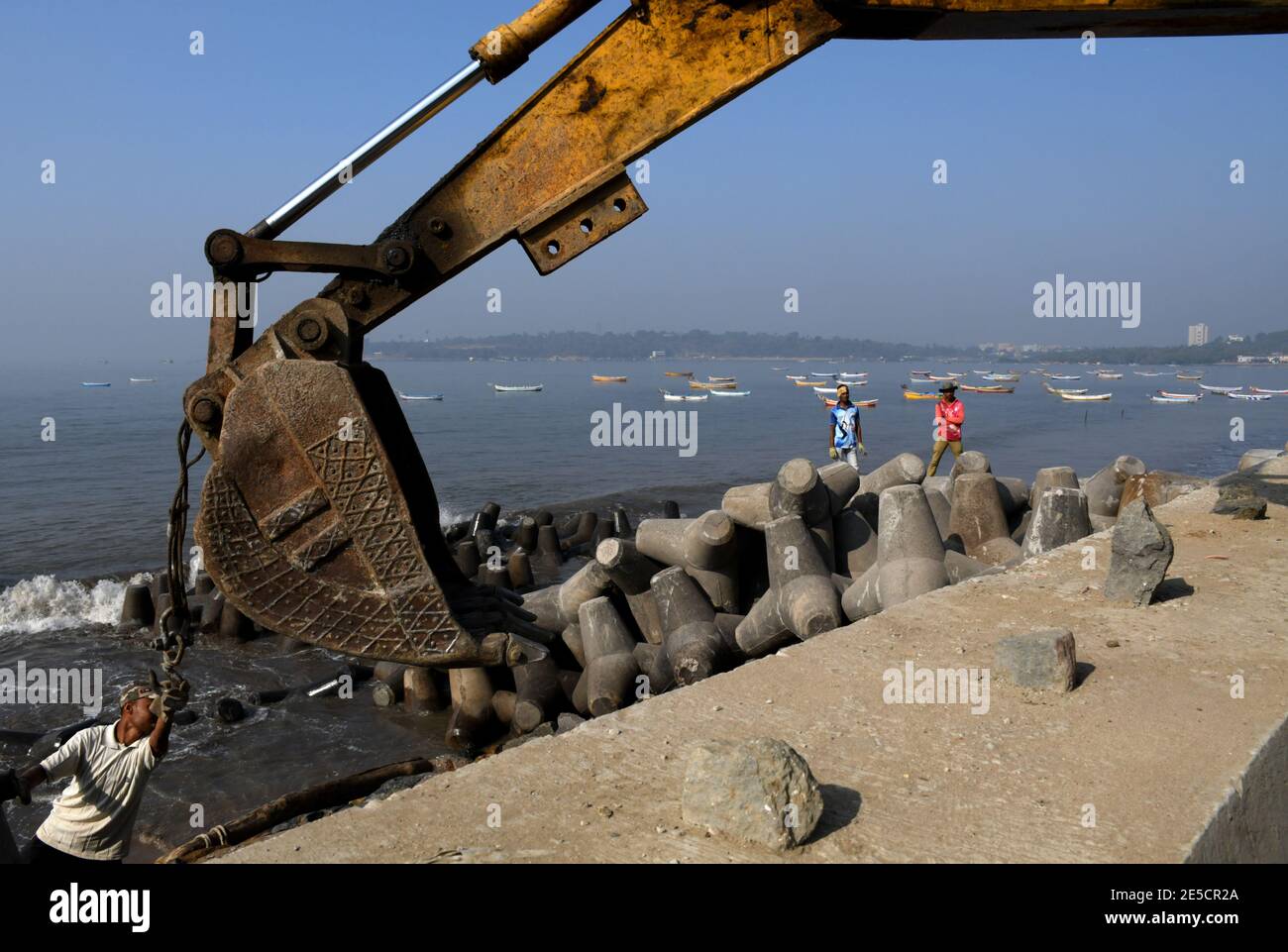 Labourers stand on a tetrapod during the tetrapod rock arrangement ...