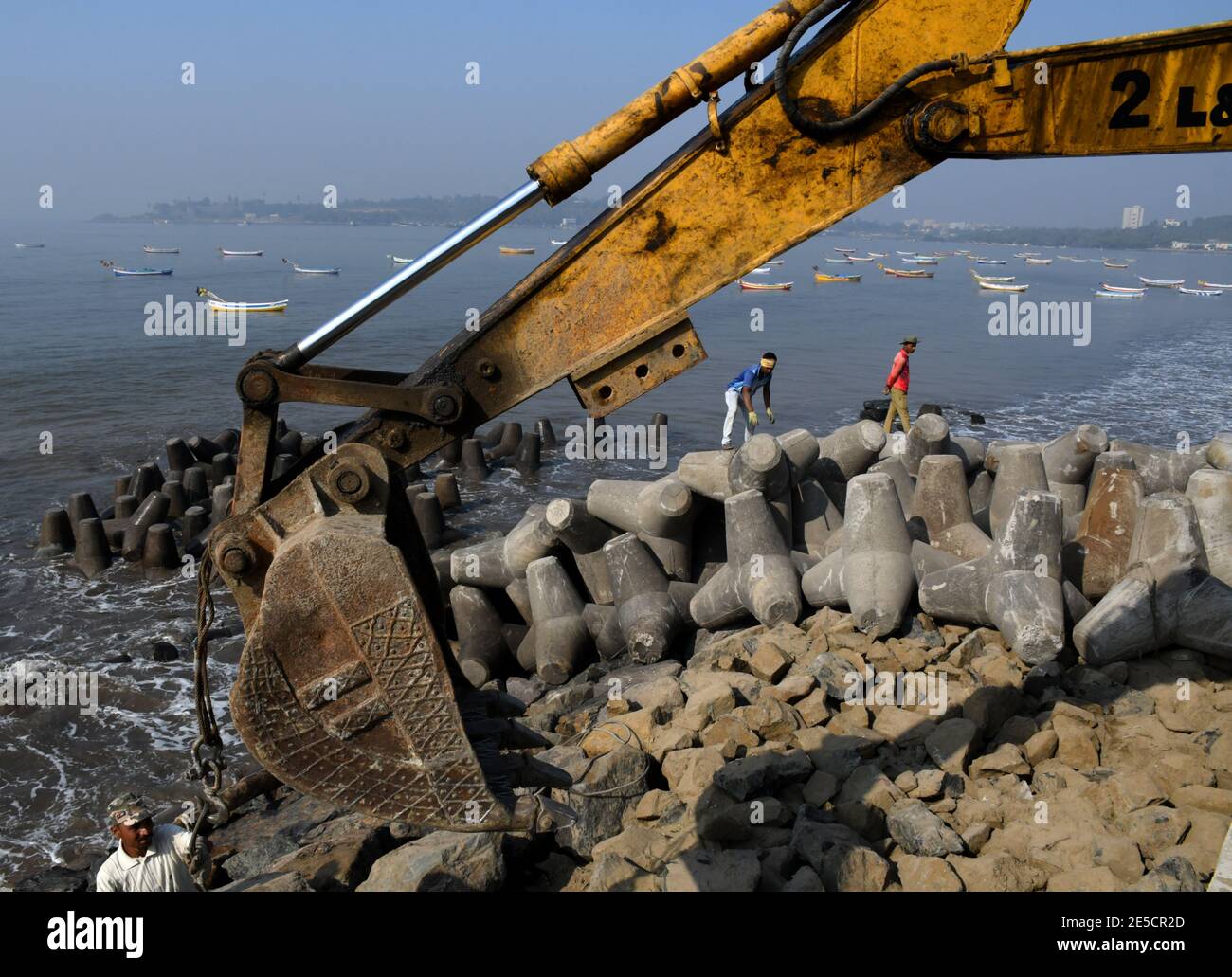 Labourers stand on a tetrapod during the tetrapod rock arrangement ...