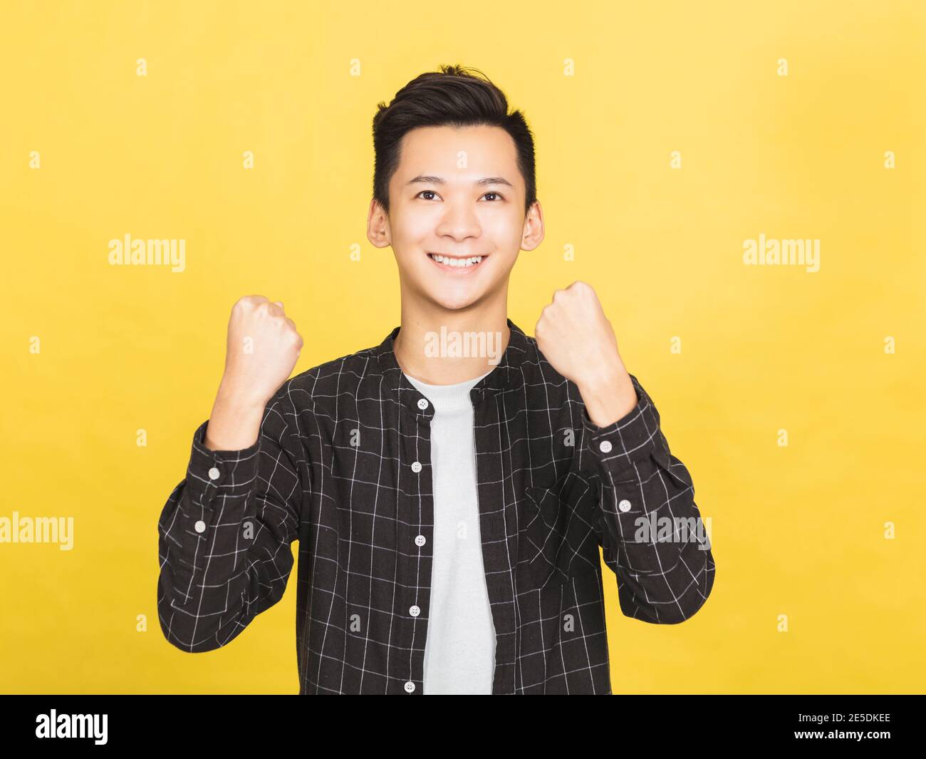 Happy young Asian man raising his fists doing yes gesture Stock Photo ...