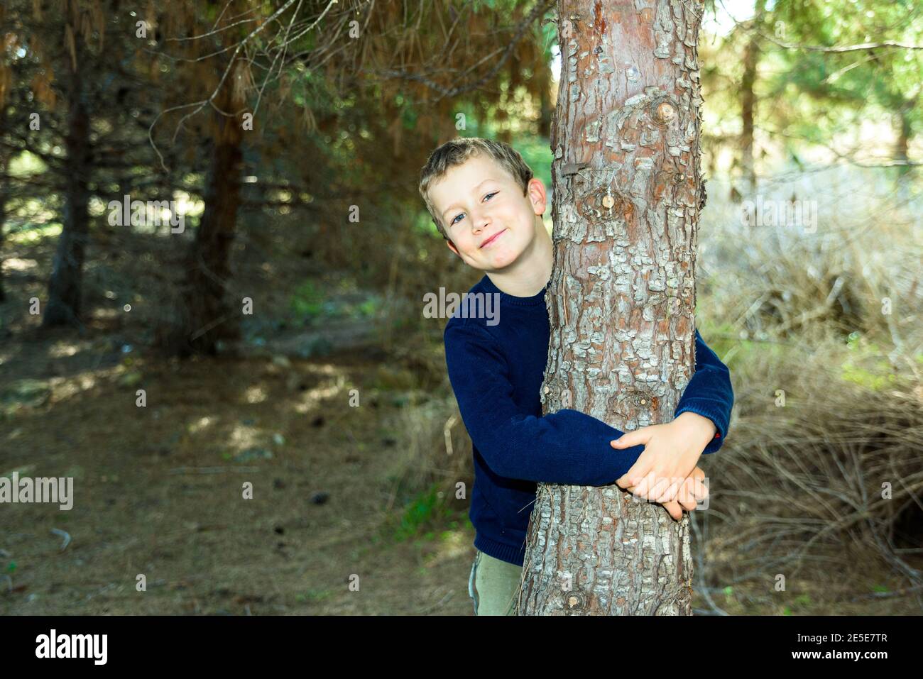Child hugging a tree in a dark forest, taking care of the planet Stock ...
