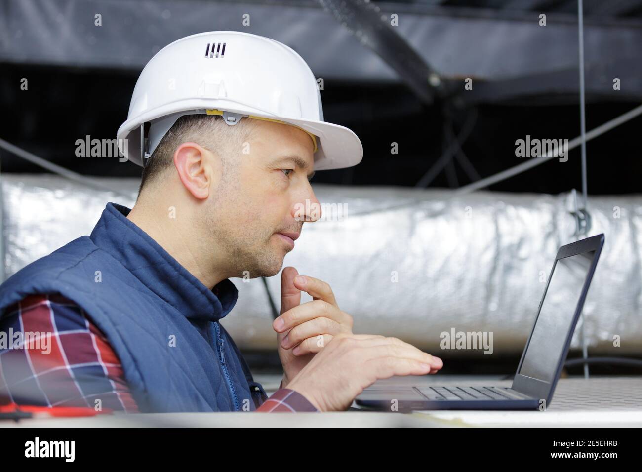 contractor using laptop in roofspace Stock Photo - Alamy