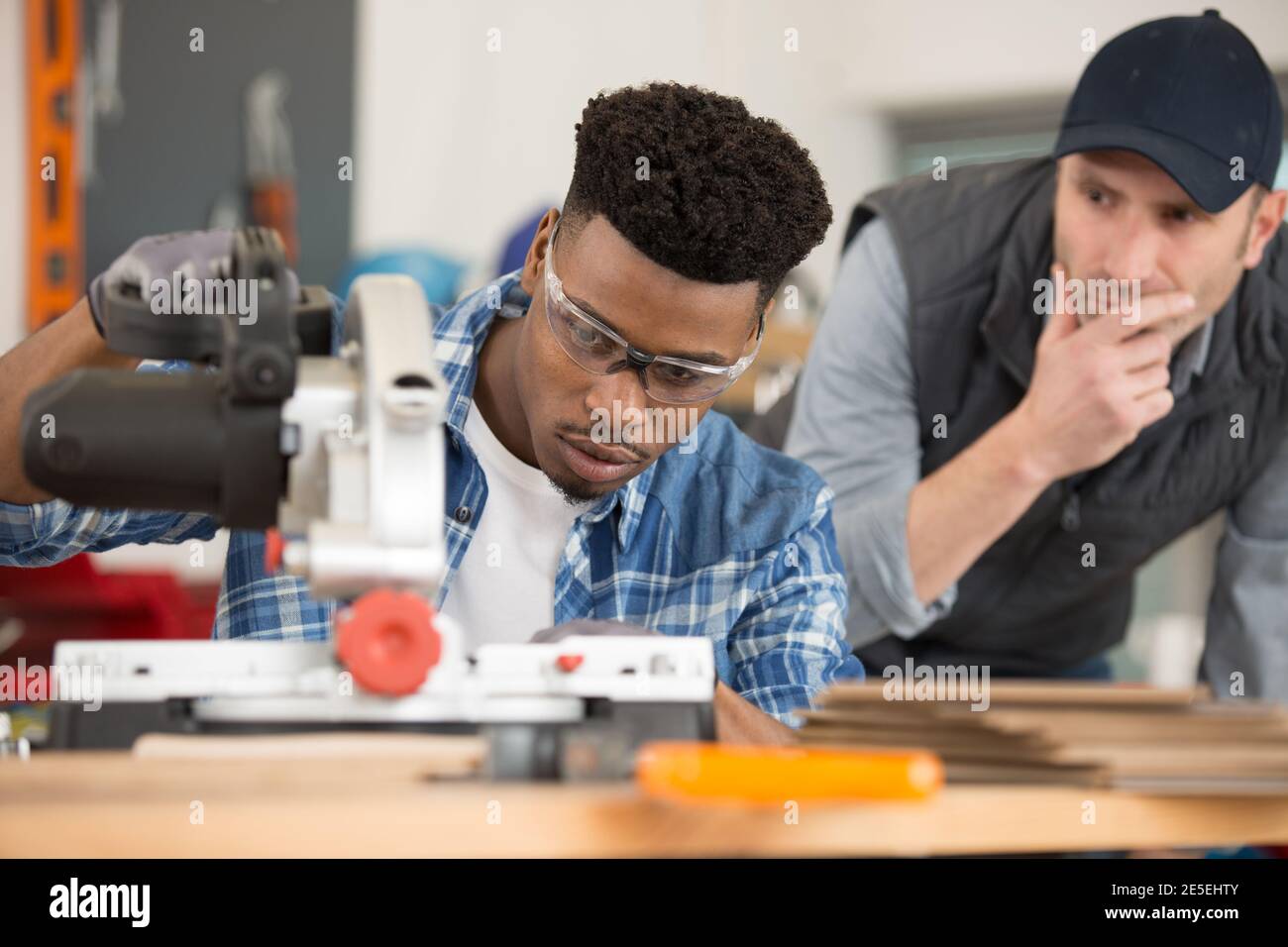 concerned supervisor watching apprentice use a circular saw Stock Photo ...