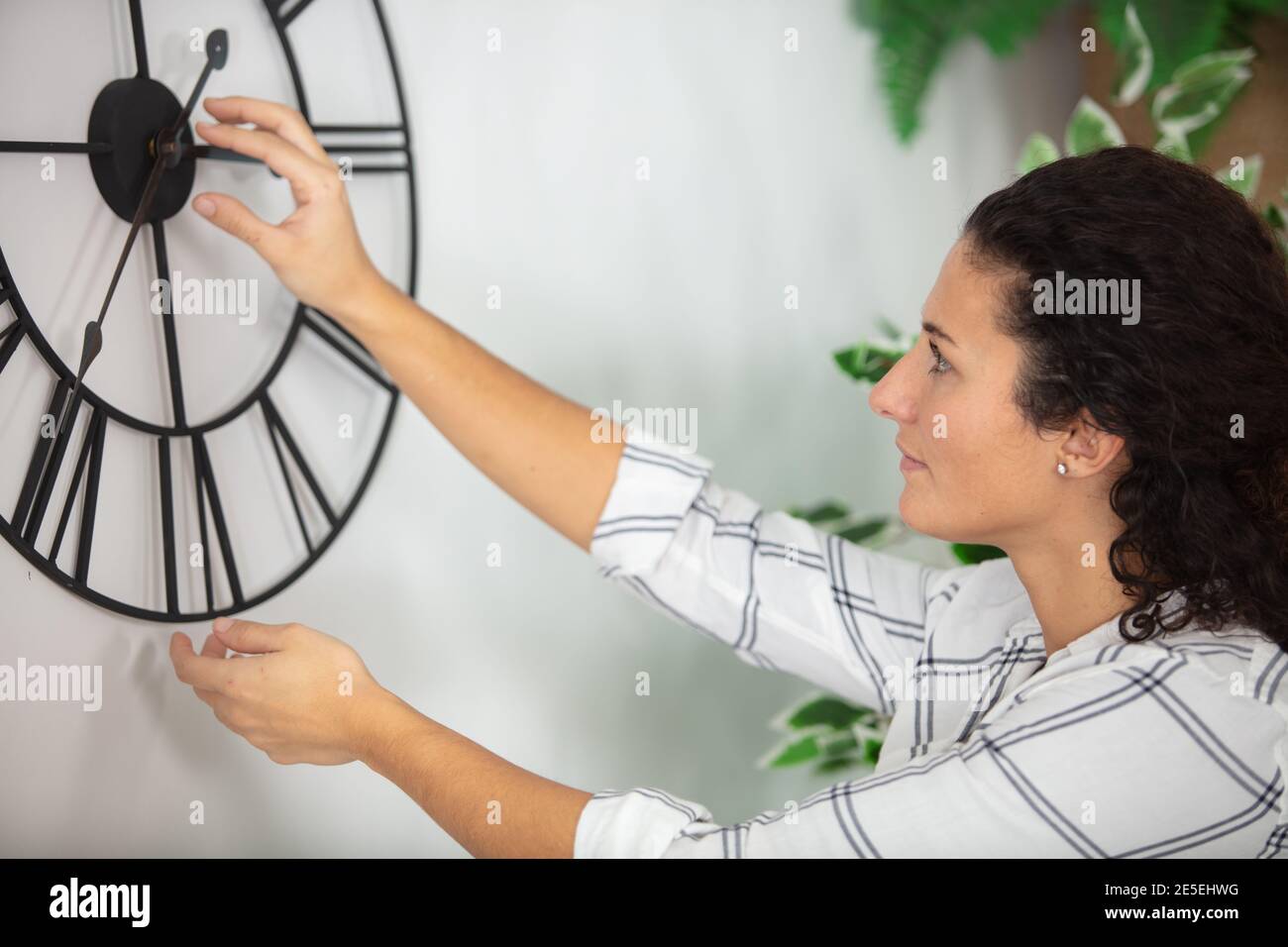 young woman setting wall clock Stock Photo - Alamy