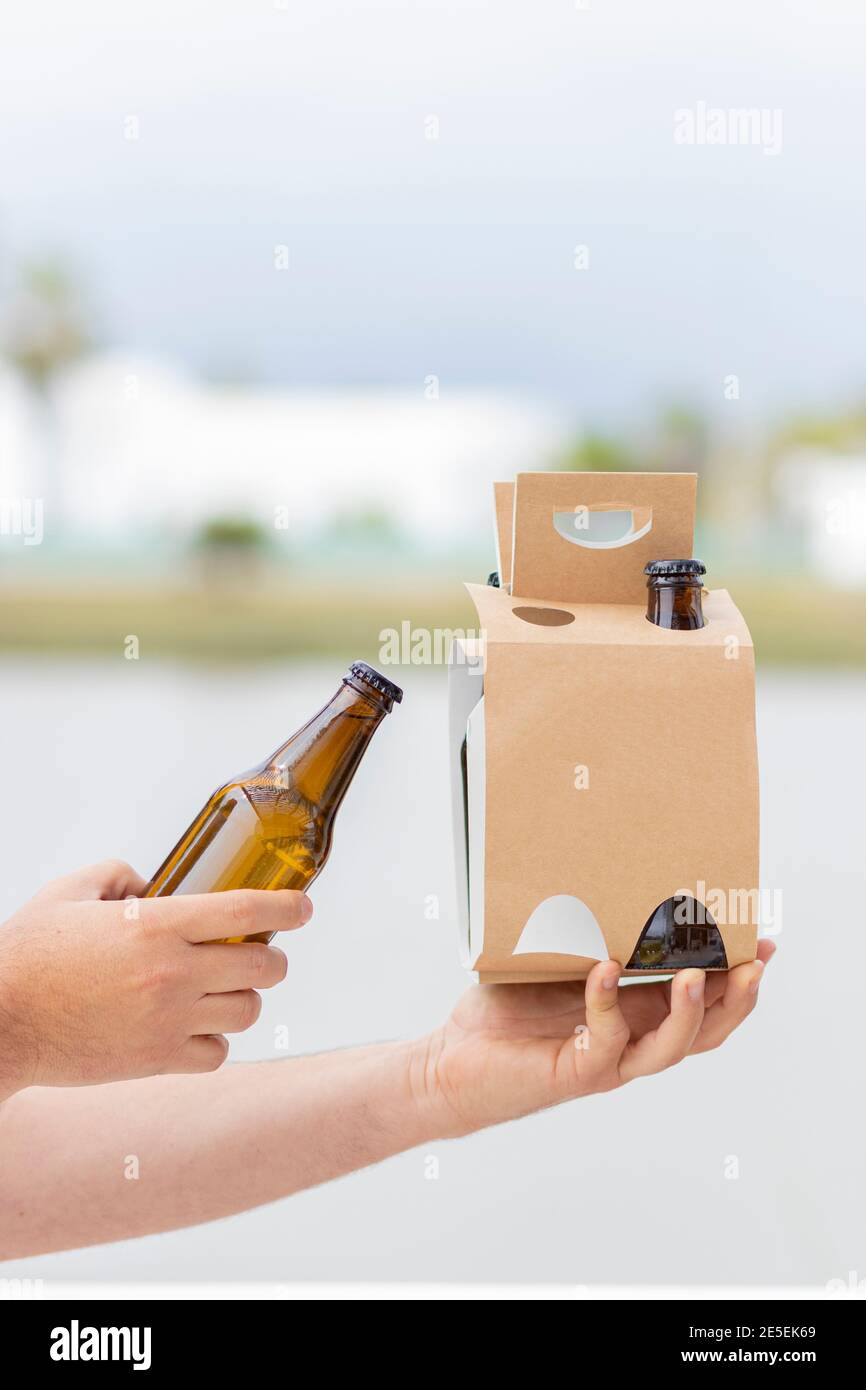Holding 4 pack of beers to celebrate on the beach Stock Photo - Alamy