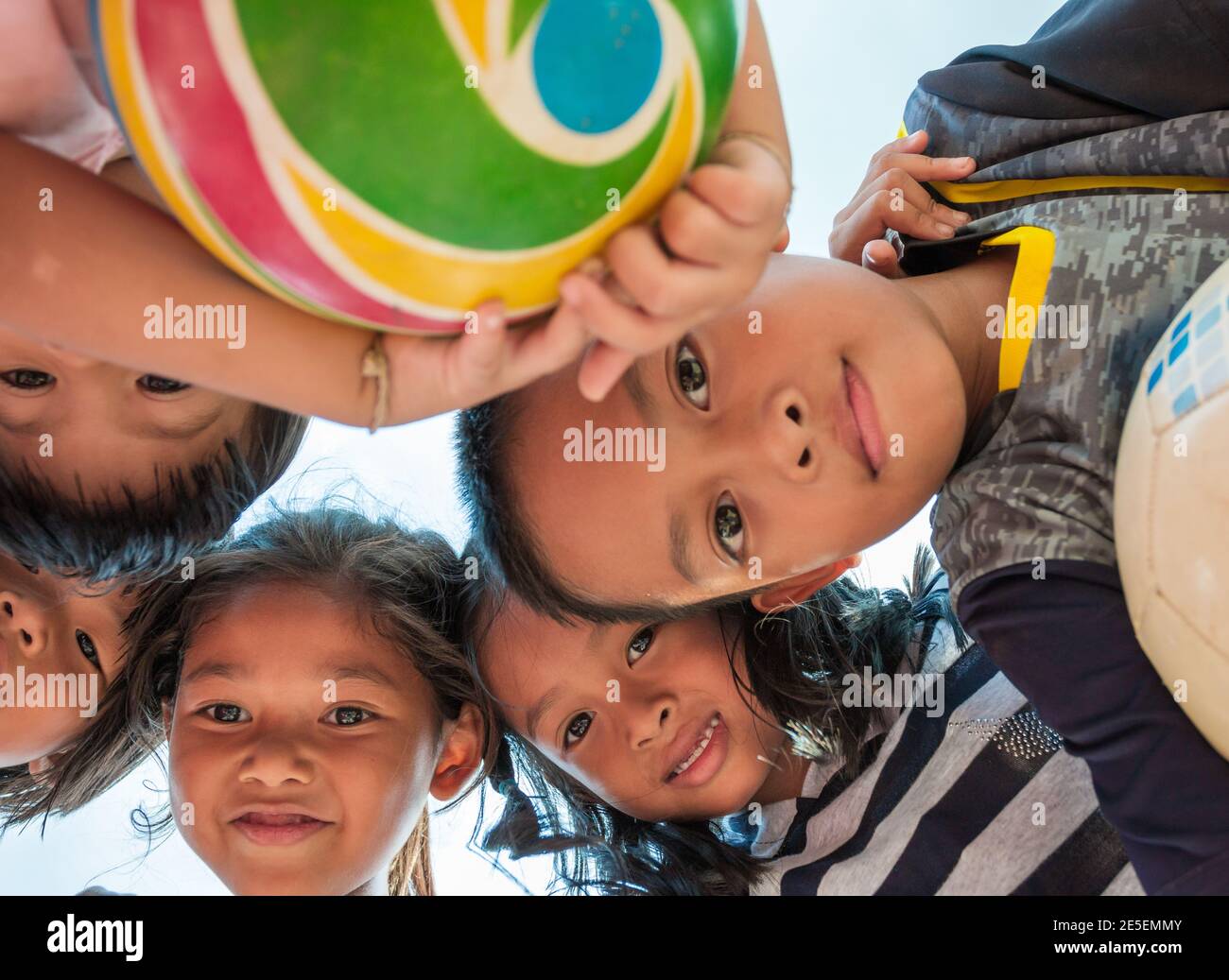 Low angle shot of excited children stand in circle hugging looking at ...