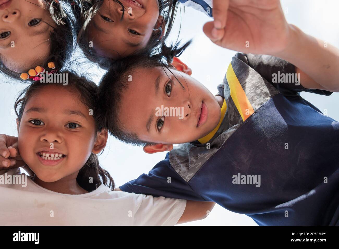 Low angle shot of excited children stand in circle hugging looking at ...