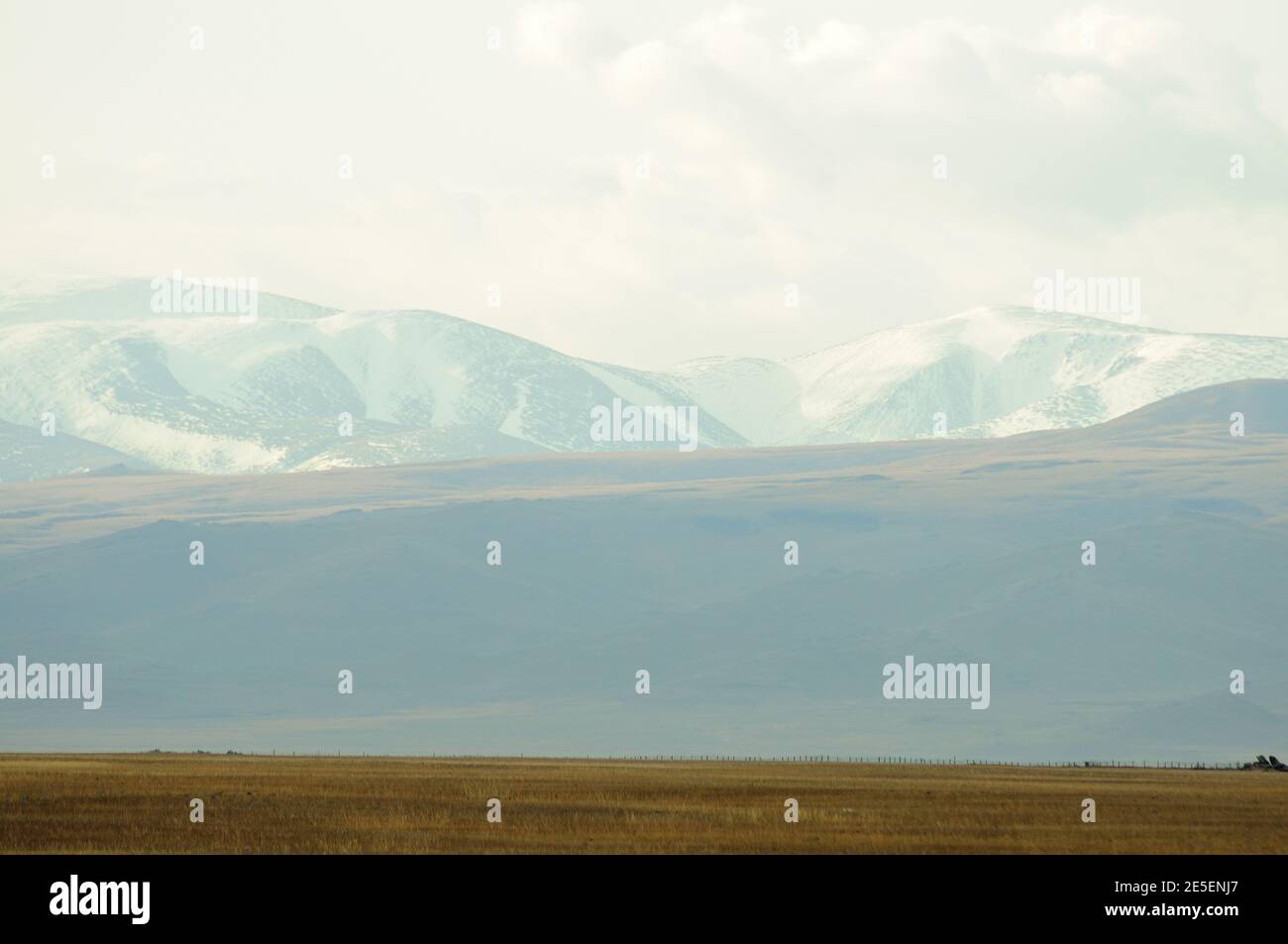Endless autumn steppe lying at the foot of a mountain range with snow ...