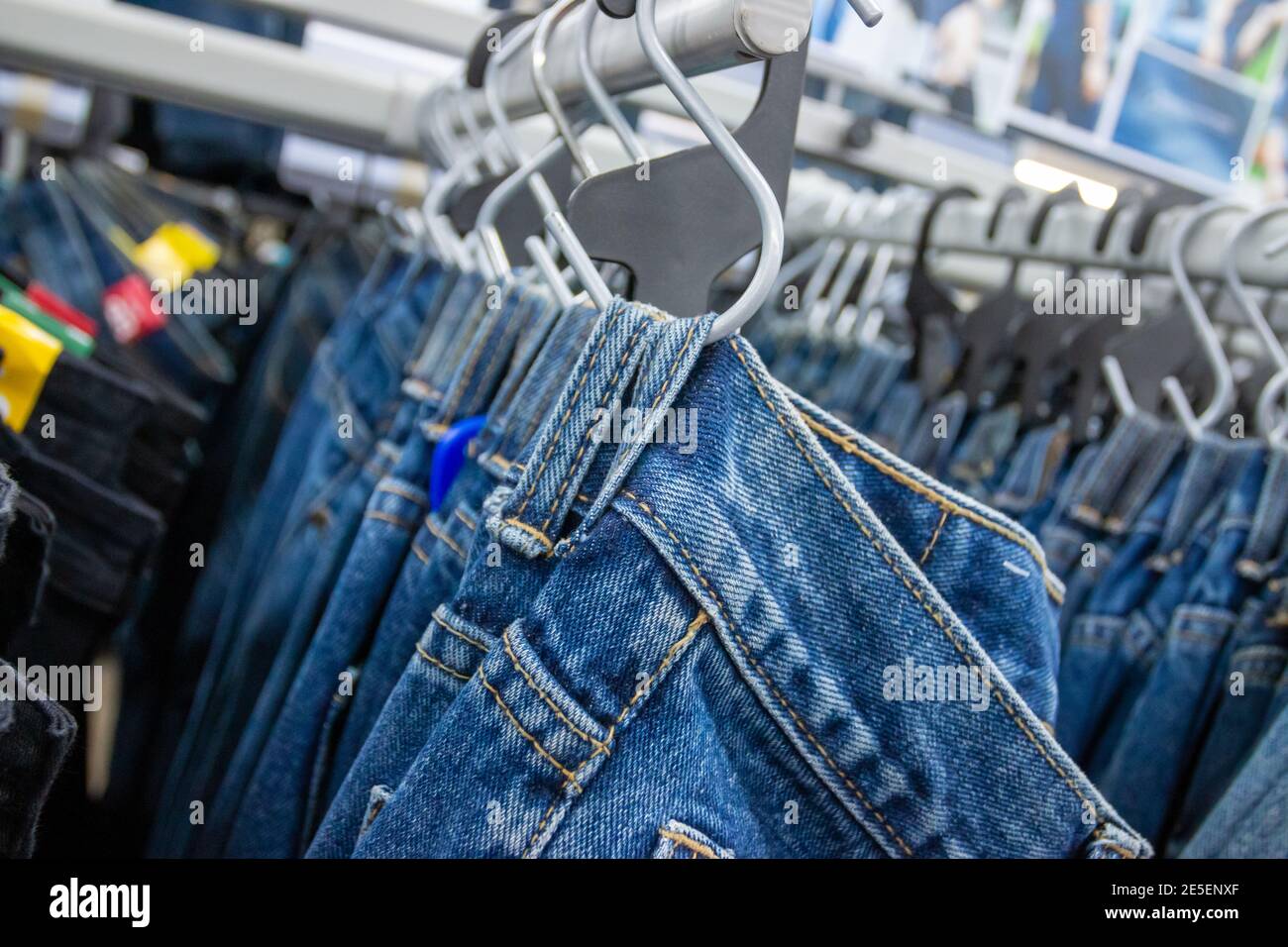 Closeup many jeans hanging on a rack. Row of pants denim jeans hanging ...
