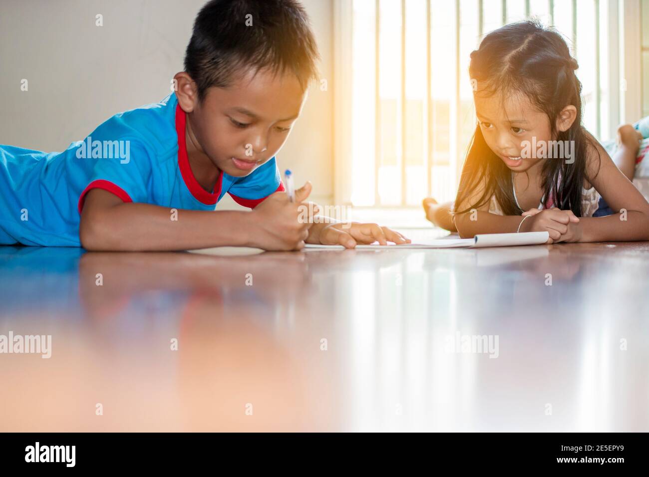 Kids sister and brother playing drawing together on wooden warm floor ...