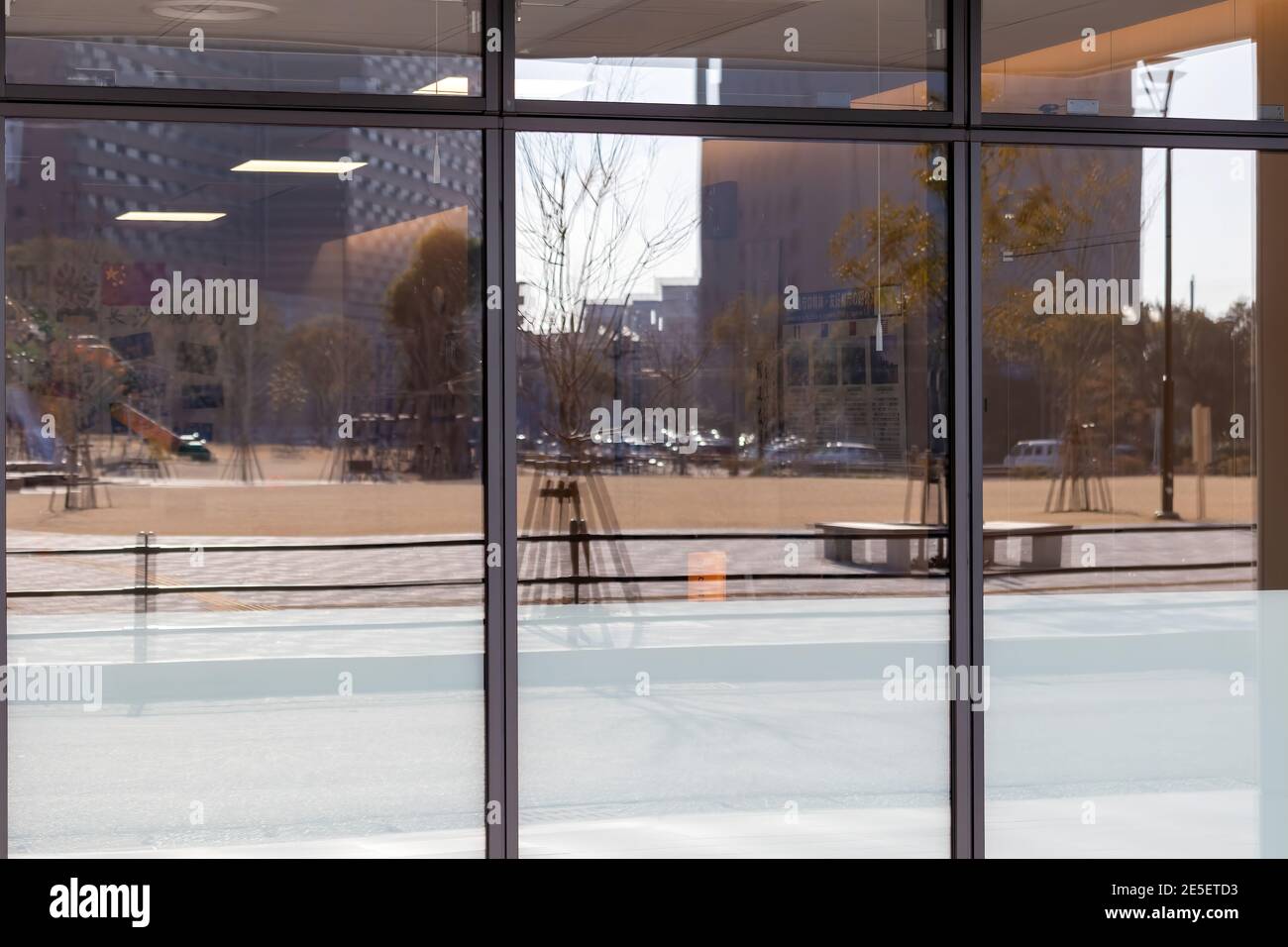 Blurred reflection of a park, cars and buildings in the windows of ...