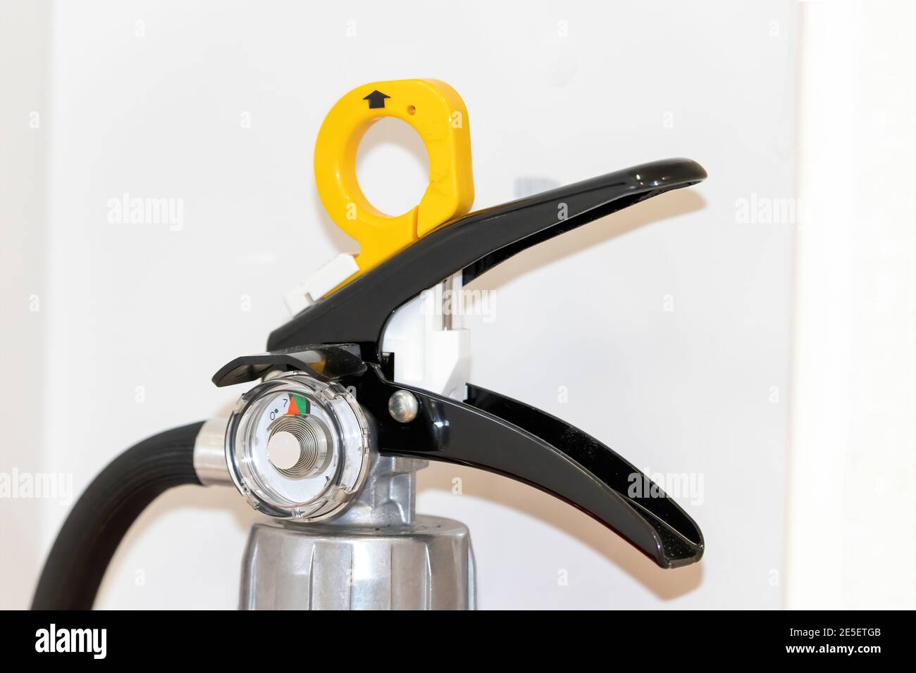 Top of a fire extinguisher, with black grip, yellow safety pin and ...