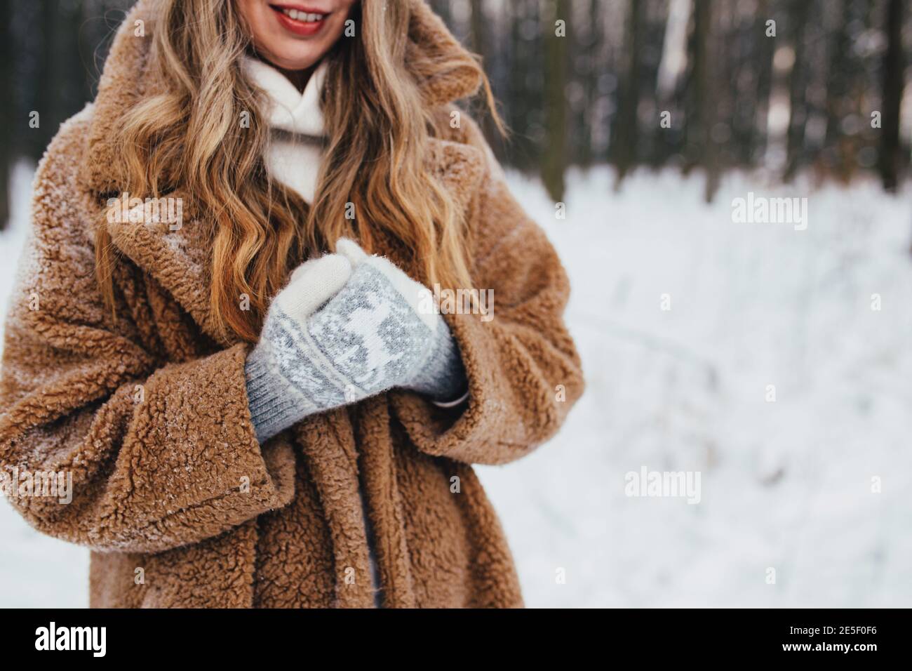 Young woman in fur coat, gloves and scarf in snowy forest. Blurred ...