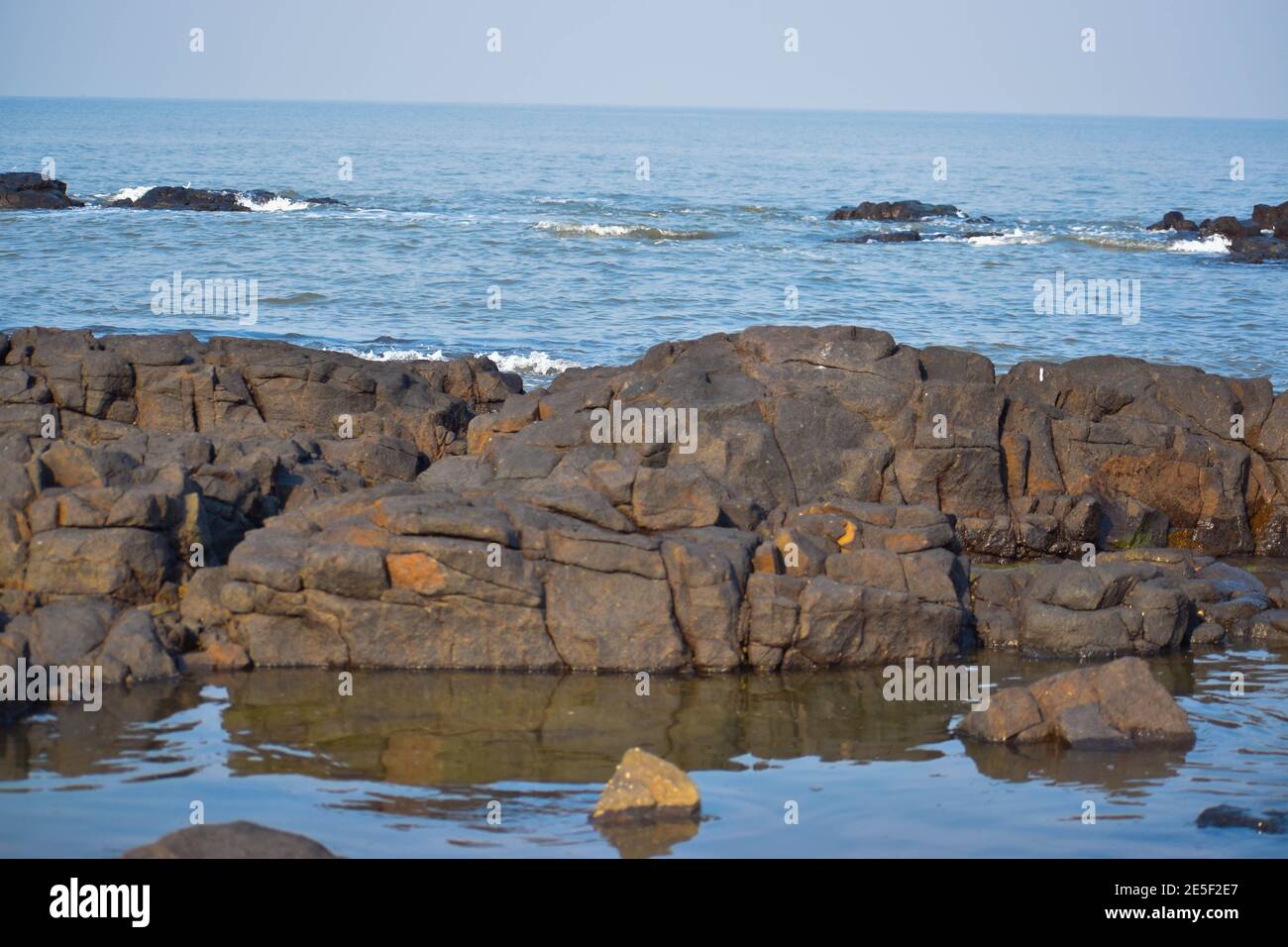 horizon of sea with coastal rocks in foreground and sky in background ...