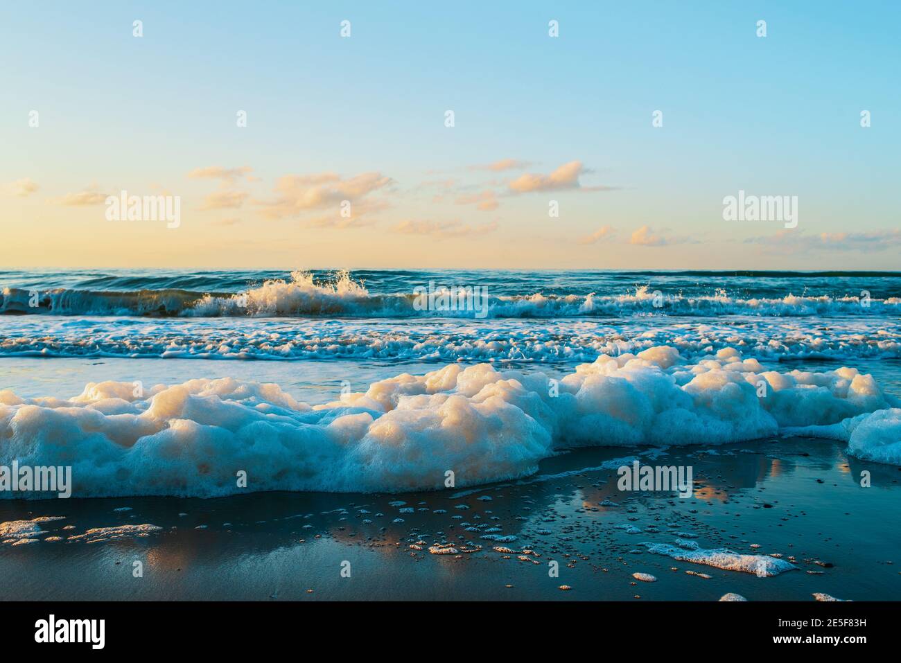 Beautiful sea, sandy beach, seafoam and clear blue sky on sunset. Wild ...