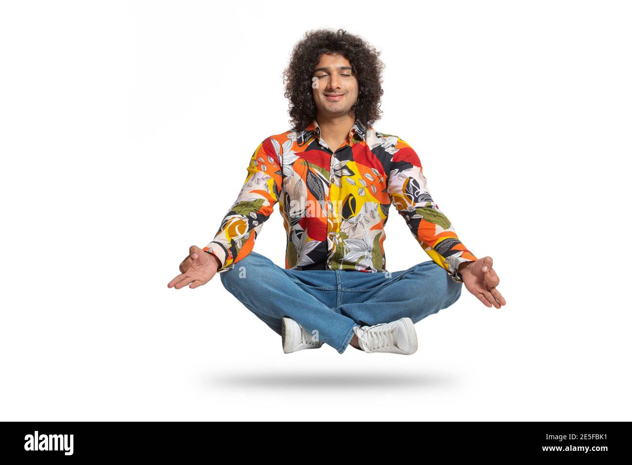 A STYLISH YOUNG MAN WITH CURLY HAIR HAPPILY MEDITATING AND RISING ABOVE ...