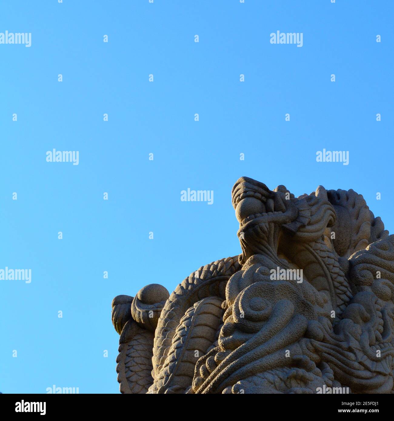 Typical Chinese stone dragon statue against a blue sky under the ...