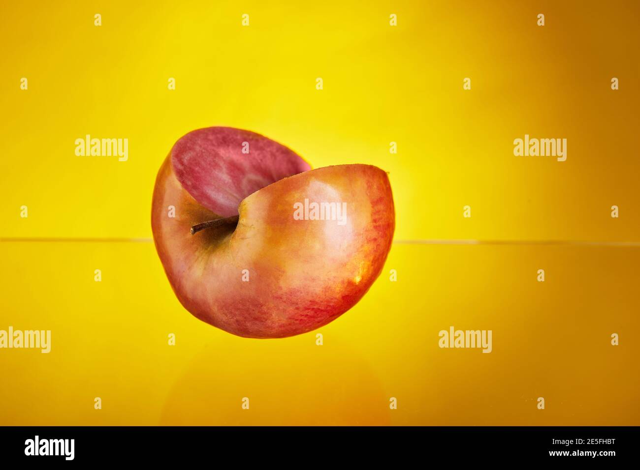 Apple with red flesh inside with a cut out wedge. Yellow background ...