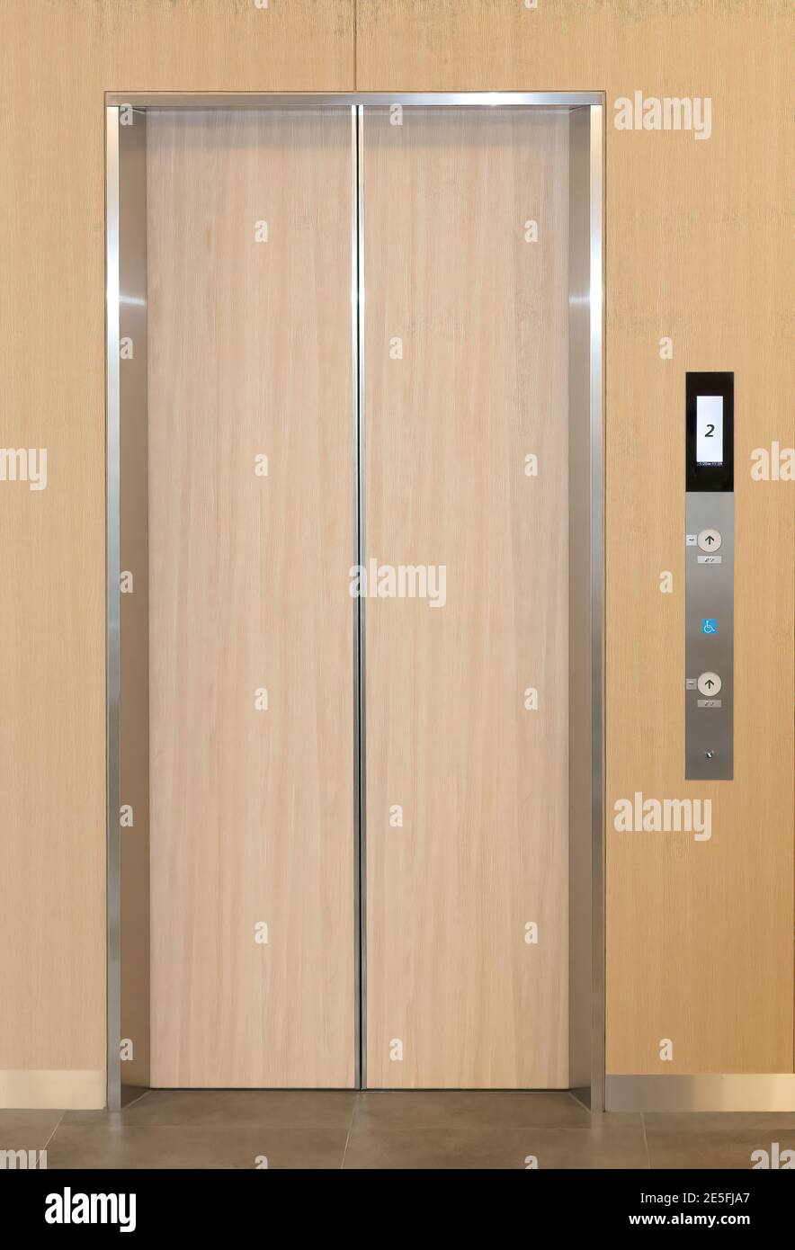 Wooden elevator door, in a shiny, polished, metal frame, with braille ...