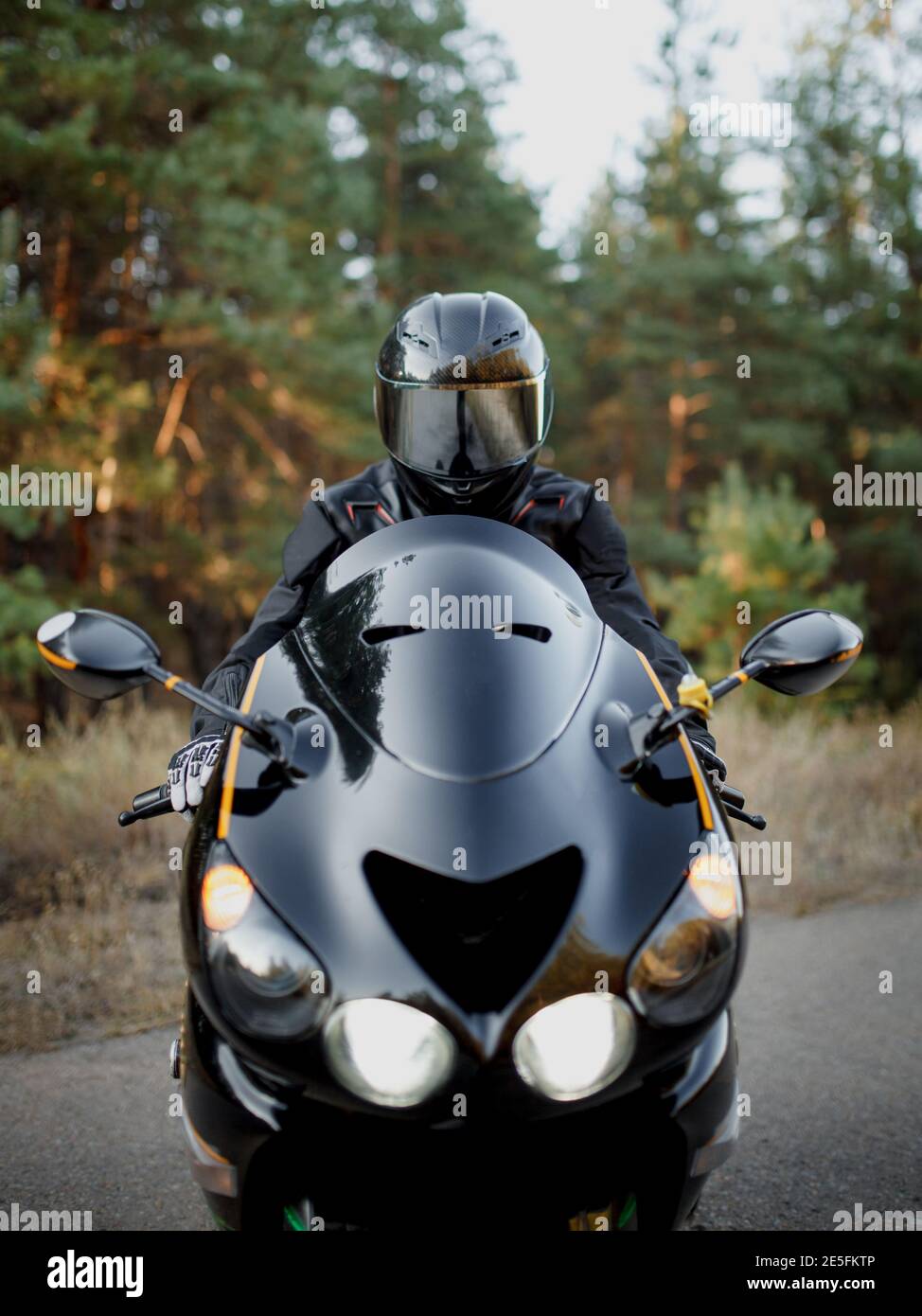 Motorcycle rider wearing a helmet looks straight ahead, headlights on ...