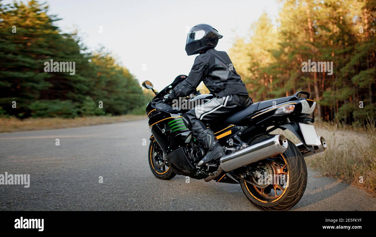 Motorcyclist alone on the road in a helmet and leather protective ...
