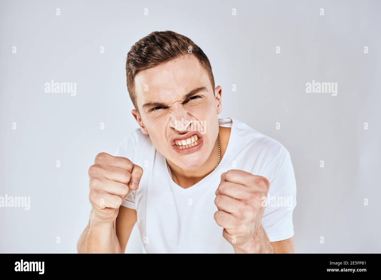 Emotional man gestures with his hands displeasure white t-shirt light ...