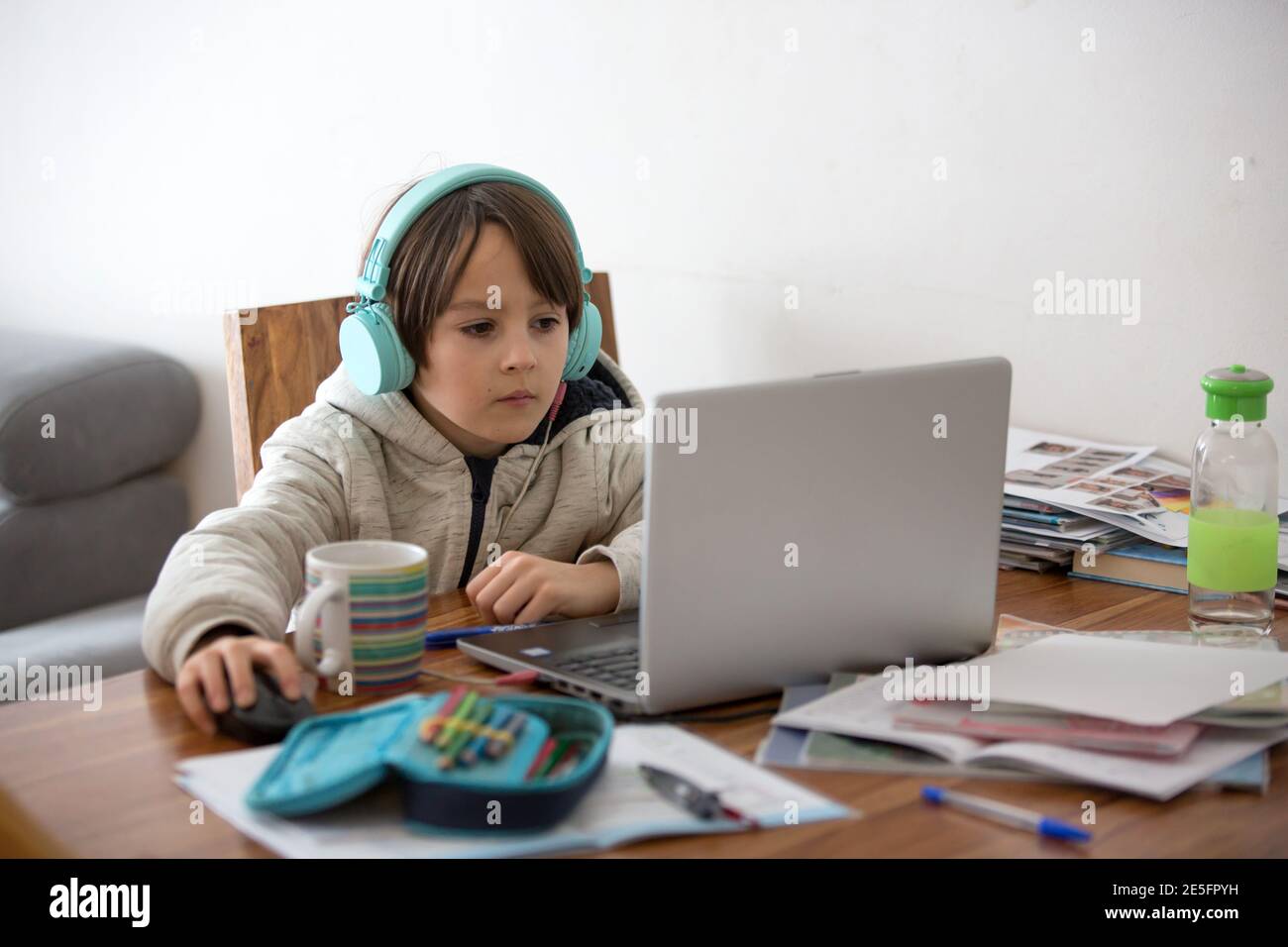 School child, sitting at the table with laptop, writing school tasks ...