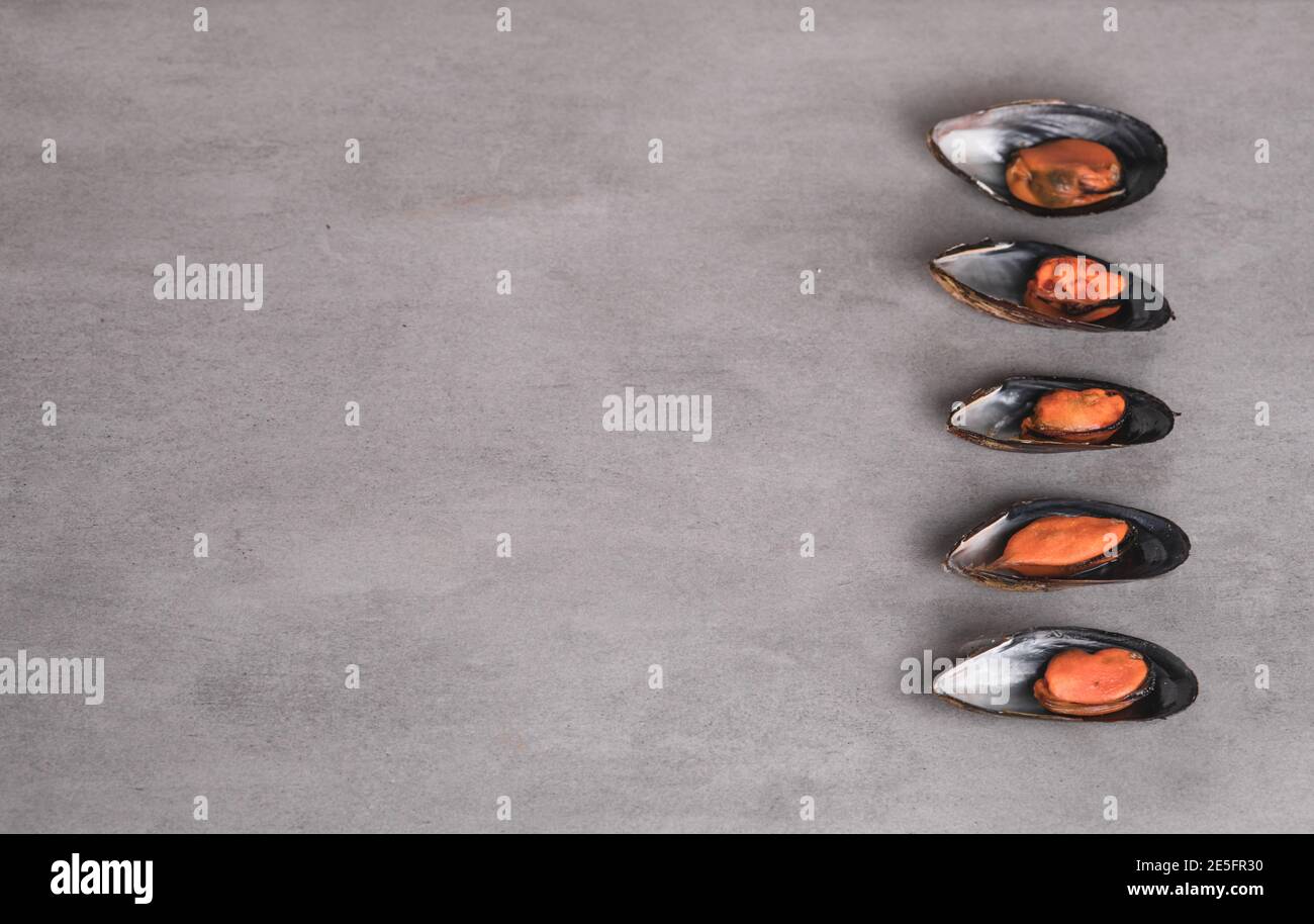 Seafood. The delicious, cooked mussels on a grey stone background ...