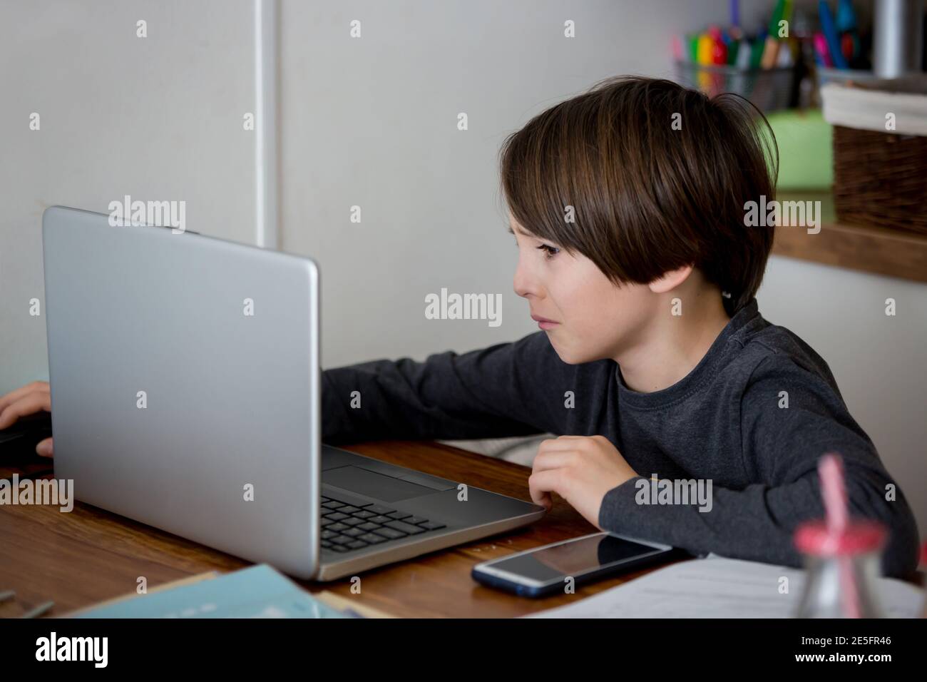 Sad school child, struggling with studying, sitting at the table with ...