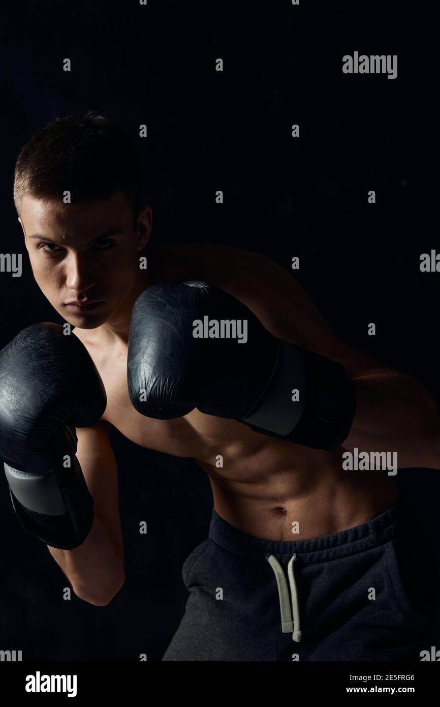 athlete in black boxing gloves on a dark background bodybuilder fitness ...