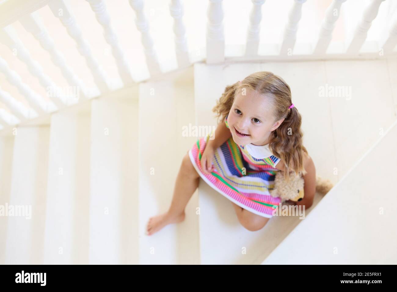 Kid walking stairs in white house. Little girl playing in sunny ...