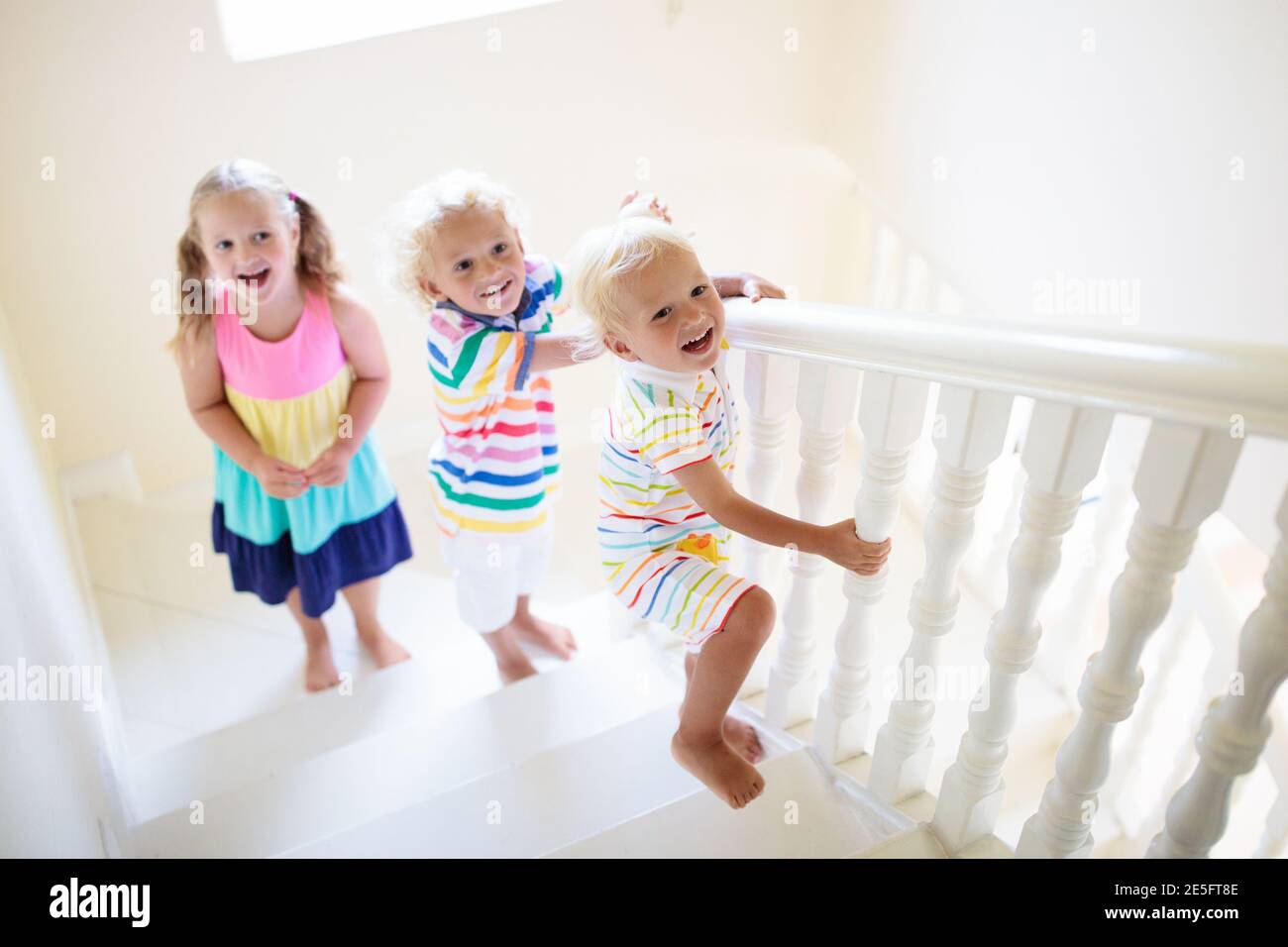 Kids walking stairs in white house. Children playing in sunny staircase ...