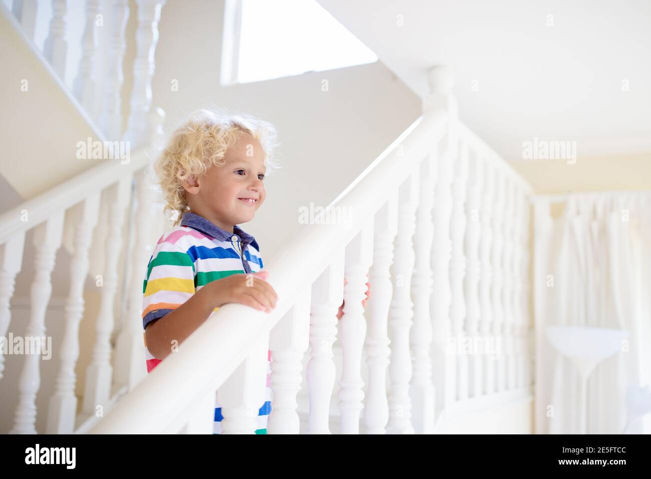 Kid walking stairs in white house. Little boy playing in sunny ...