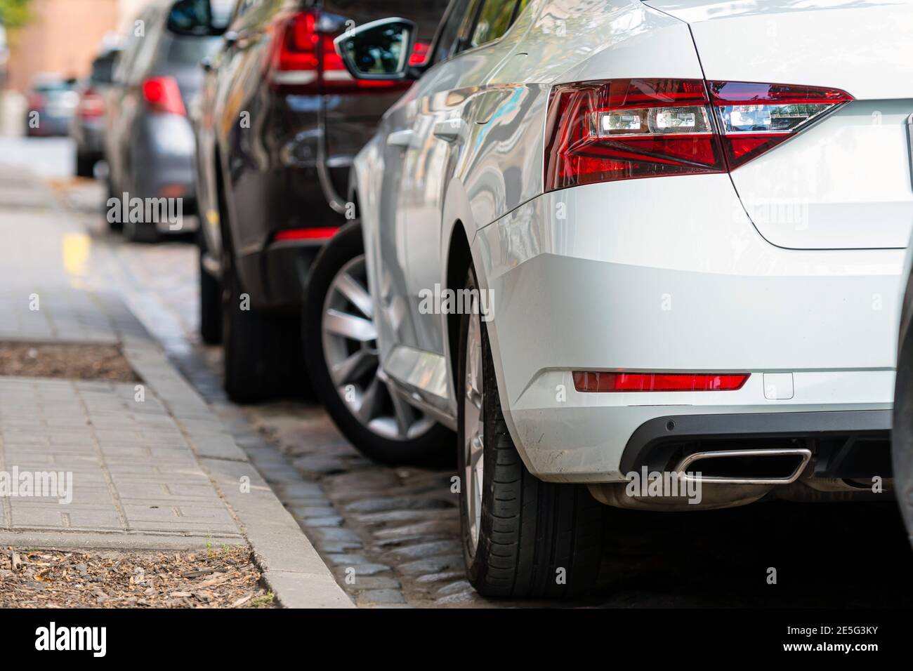 rows of different cars parked along the roadside in crowded city Stock ...