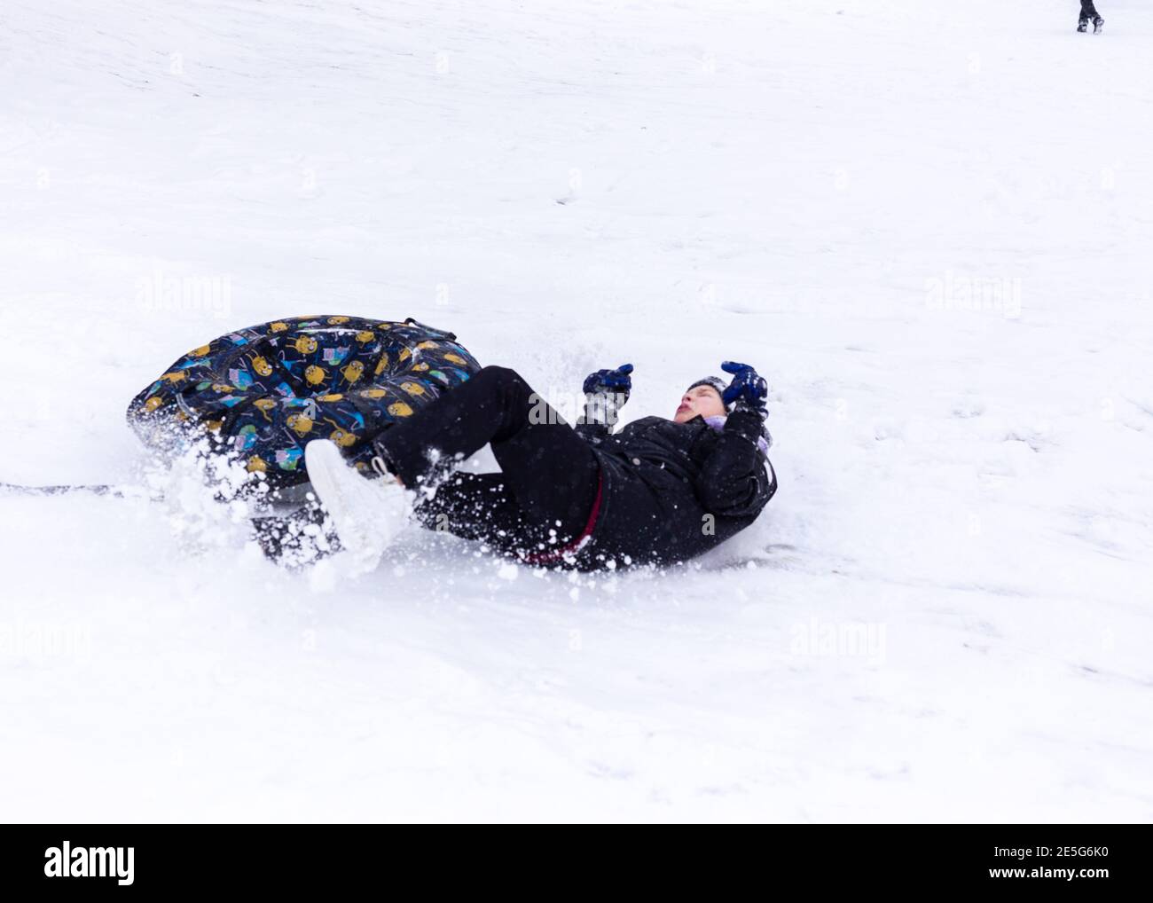 A boy rides a tubing from a snow slide and rolls over Stock Photo - Alamy