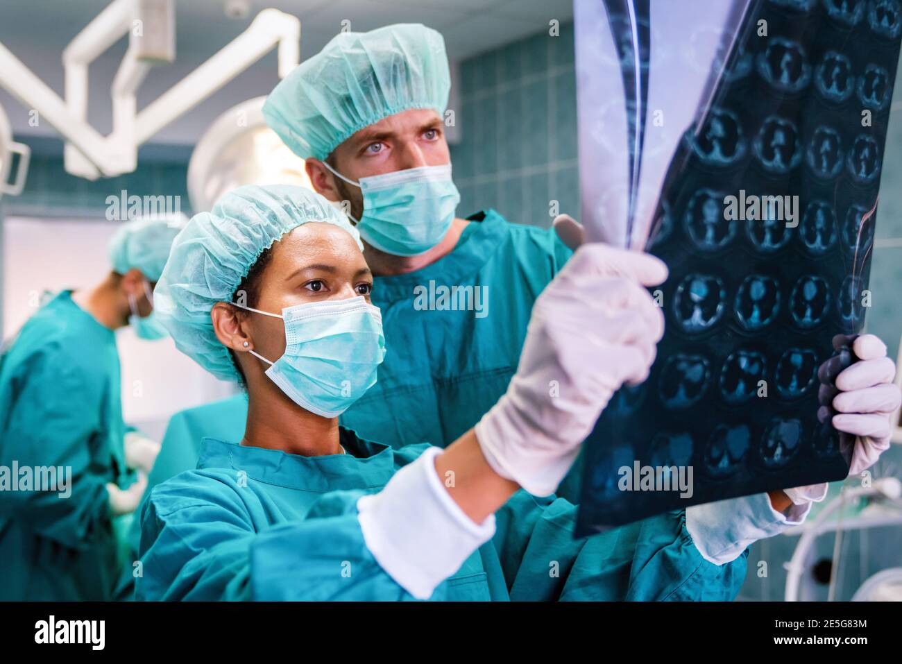Team of surgeon doctors looking at x-ray film before surgery to set up ...