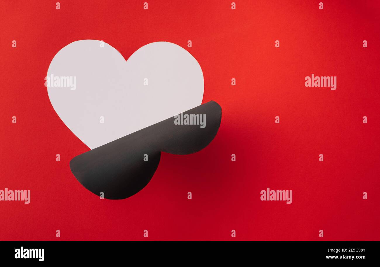 Black heart shape cut and peeled back to reveal white symbol of love ...